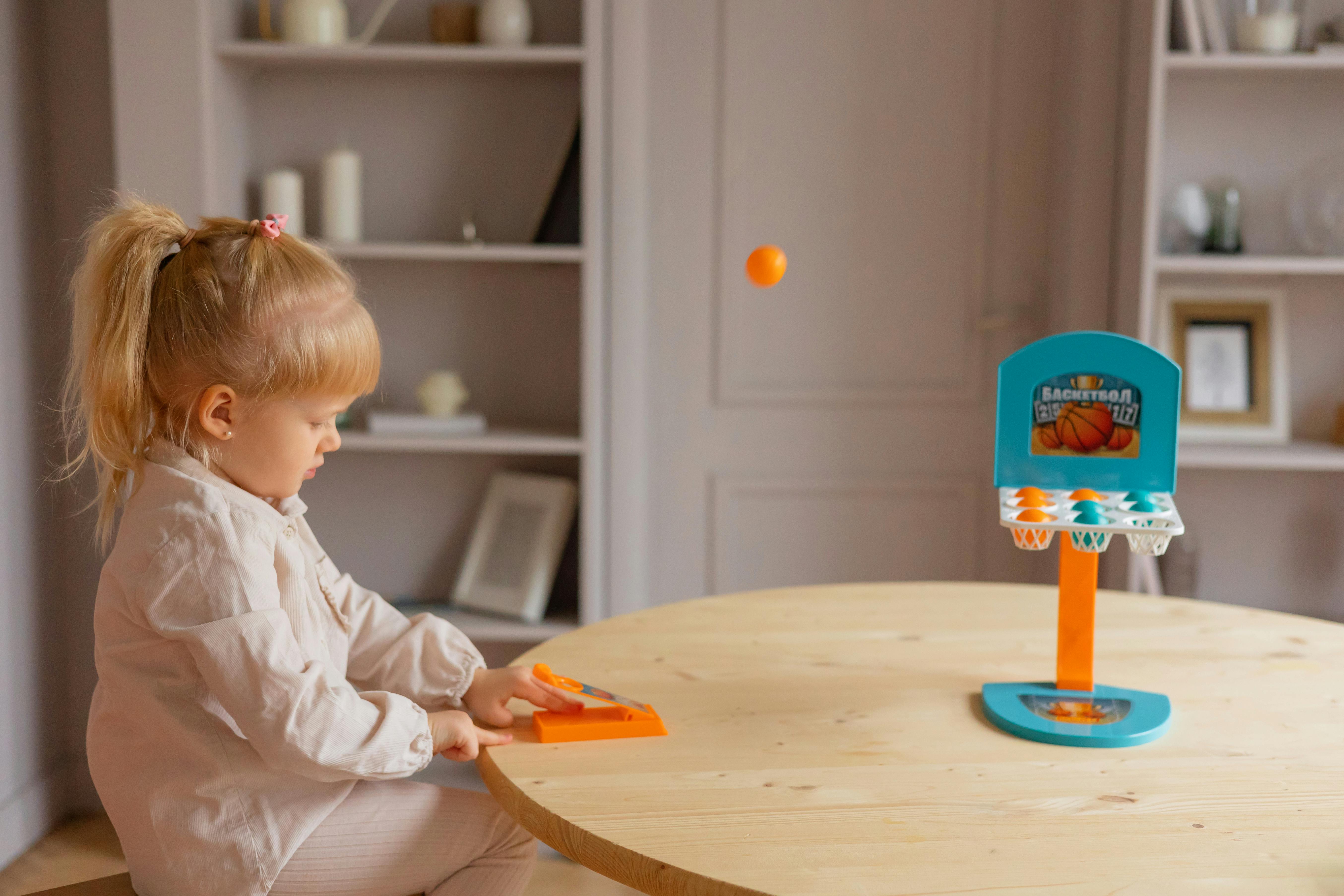 Blonde Girl Sitting and Playing with Toy Catapult · Free Stock Photo