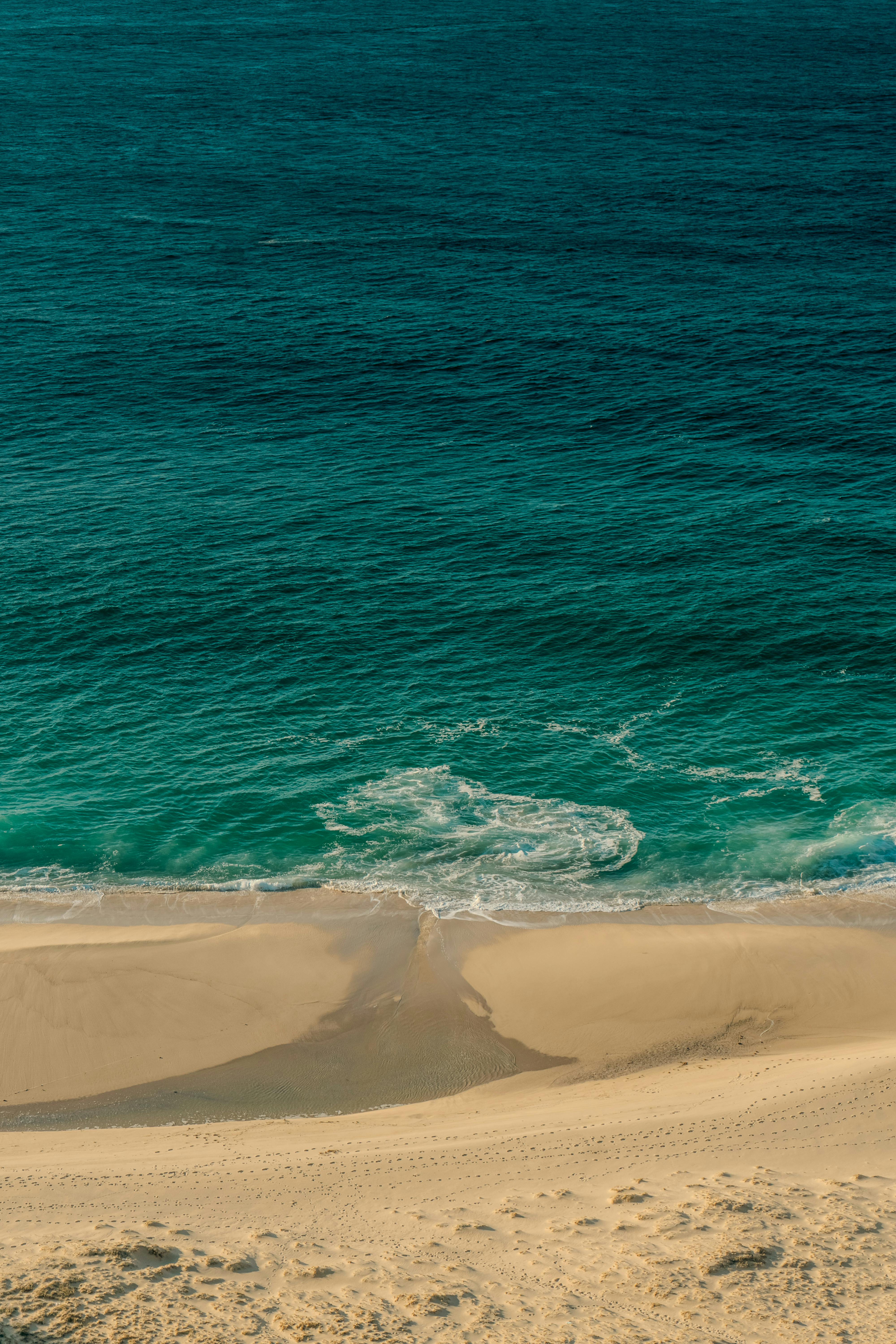 A beach with a sandy shore and ocean · Free Stock Photo