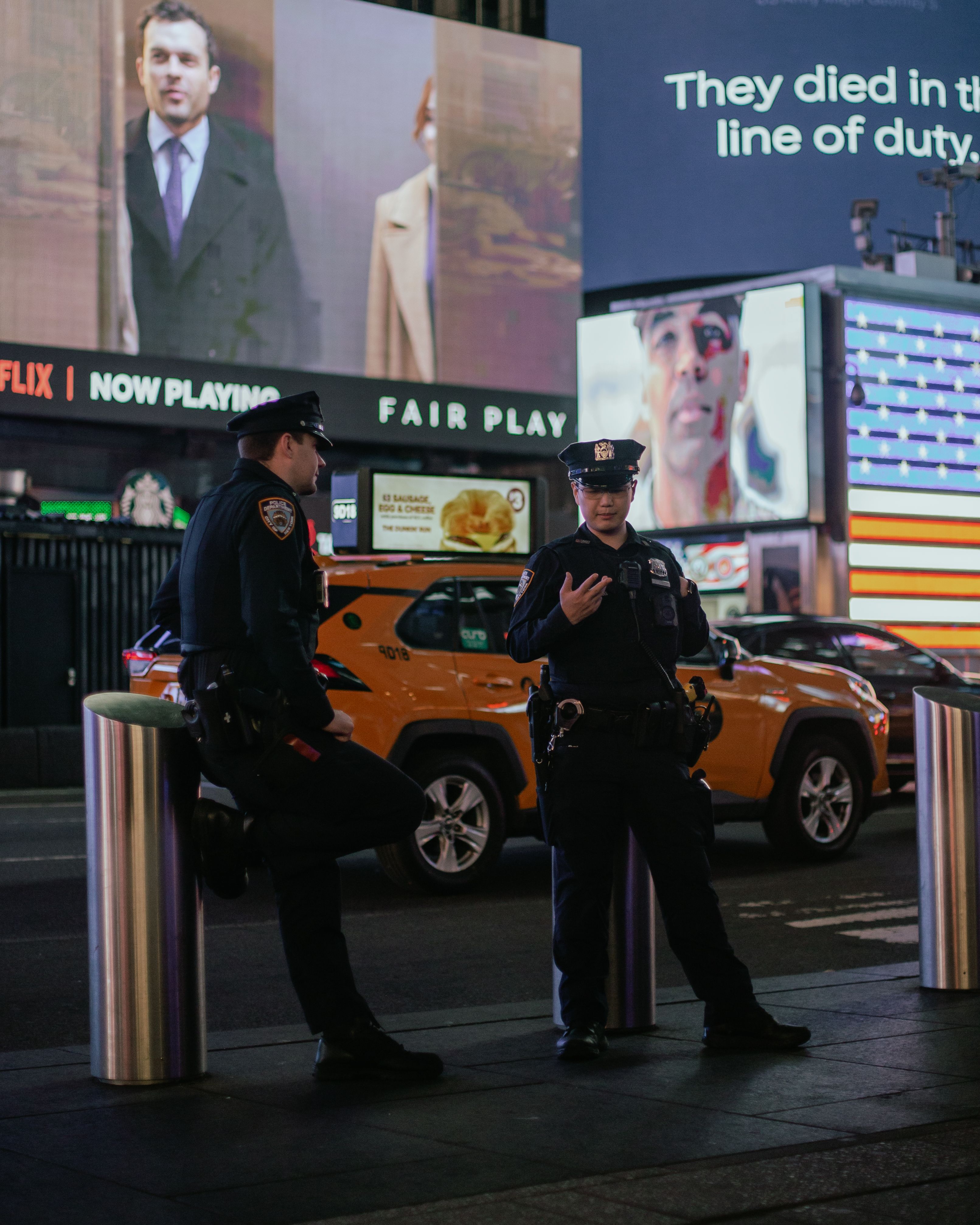 Two police officers stand in front of a large screen · Free Stock Photo