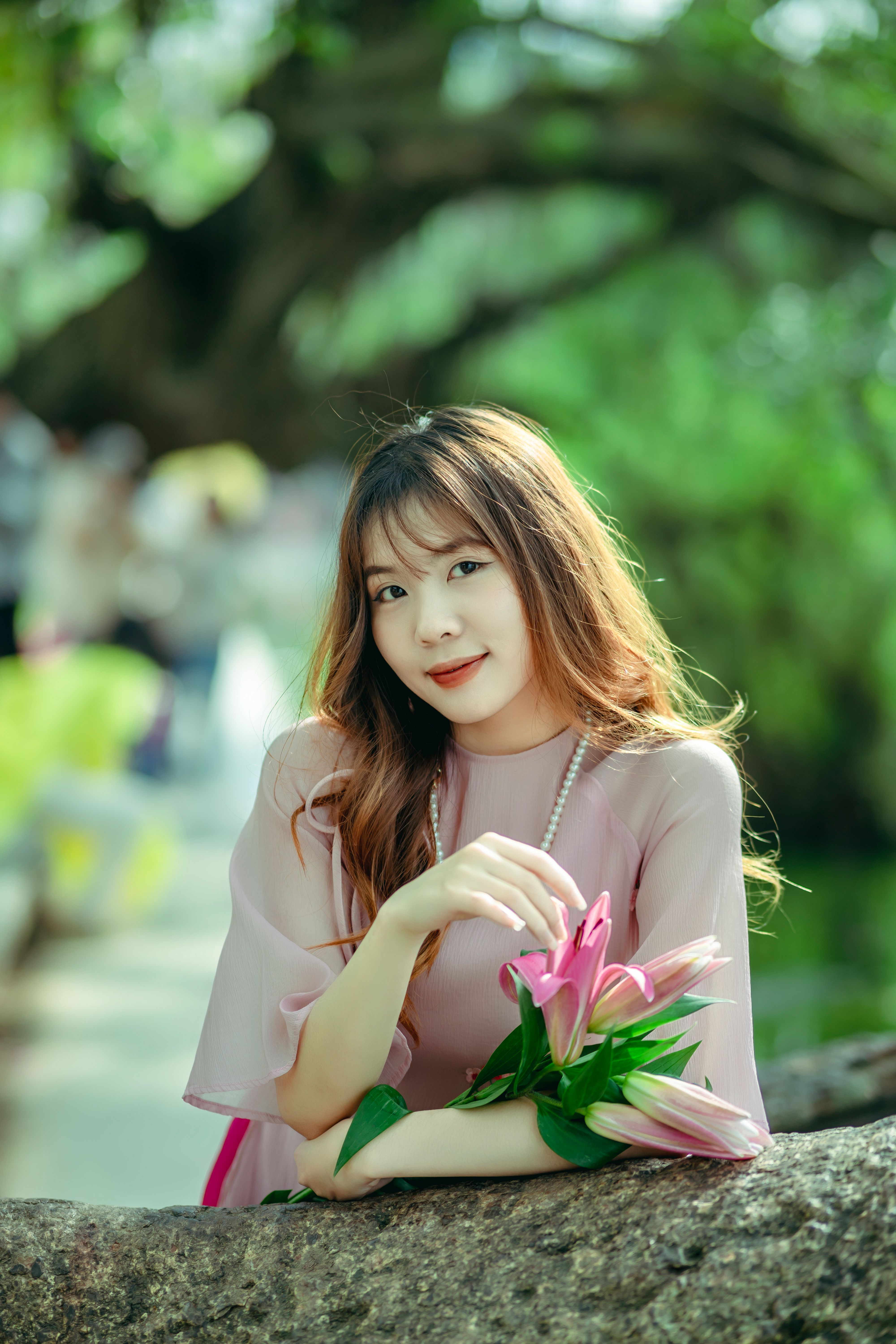 A Smiling Young Woman with Lilies · Free Stock Photo