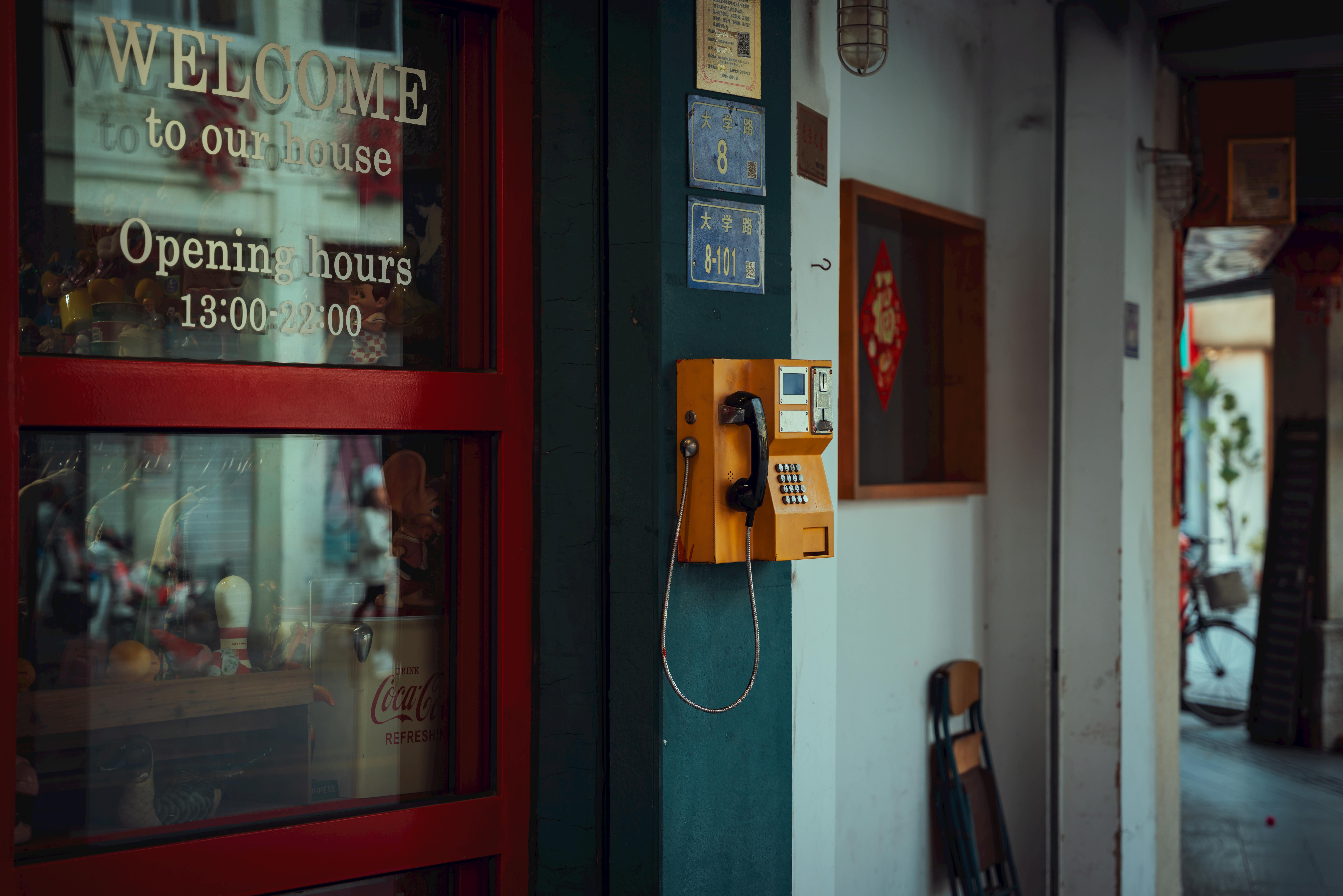 Orange Payphone on a Wall by a Glass Door · Free Stock Photo
