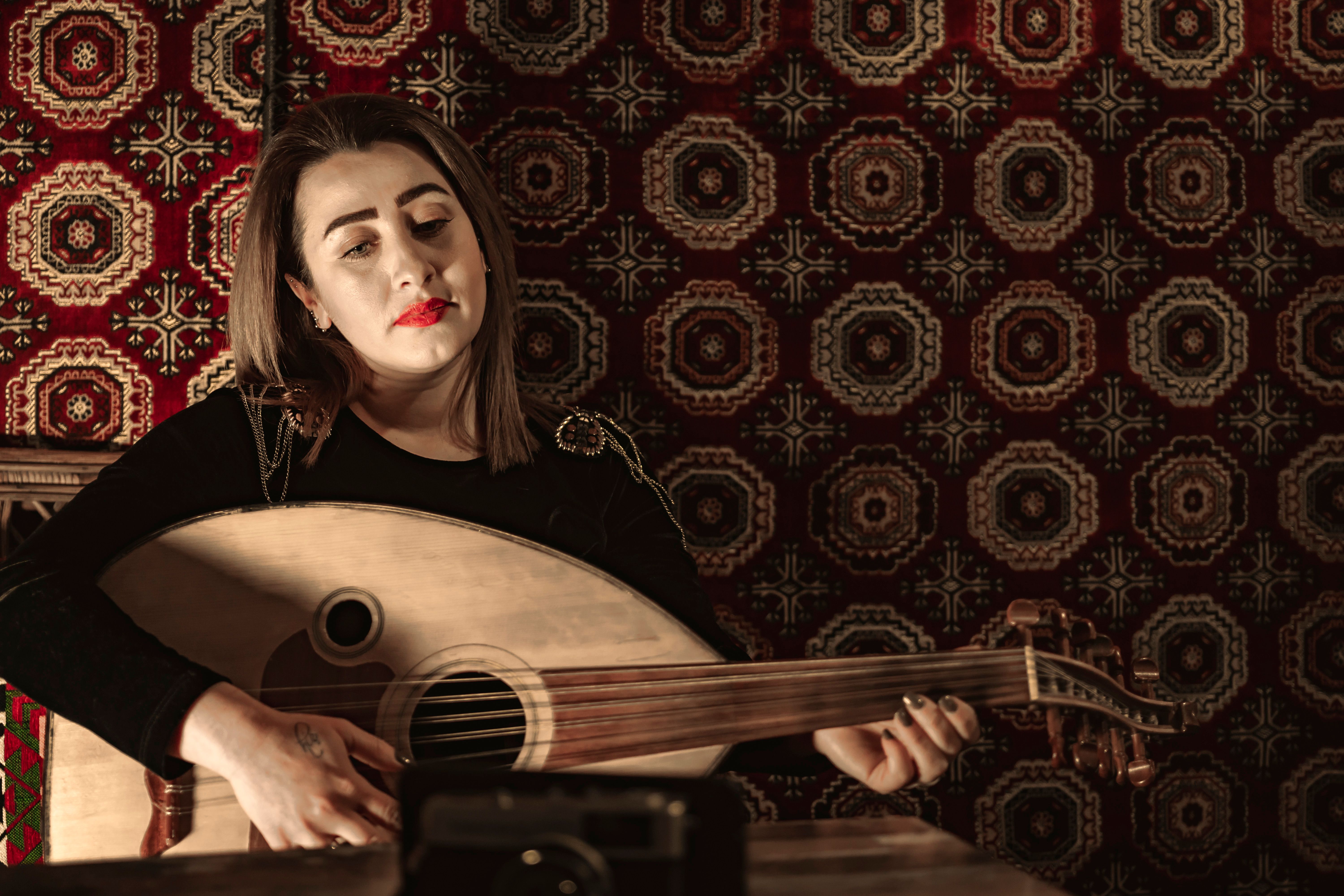 Young Woman Sitting and Playing an Oud · Free Stock Photo