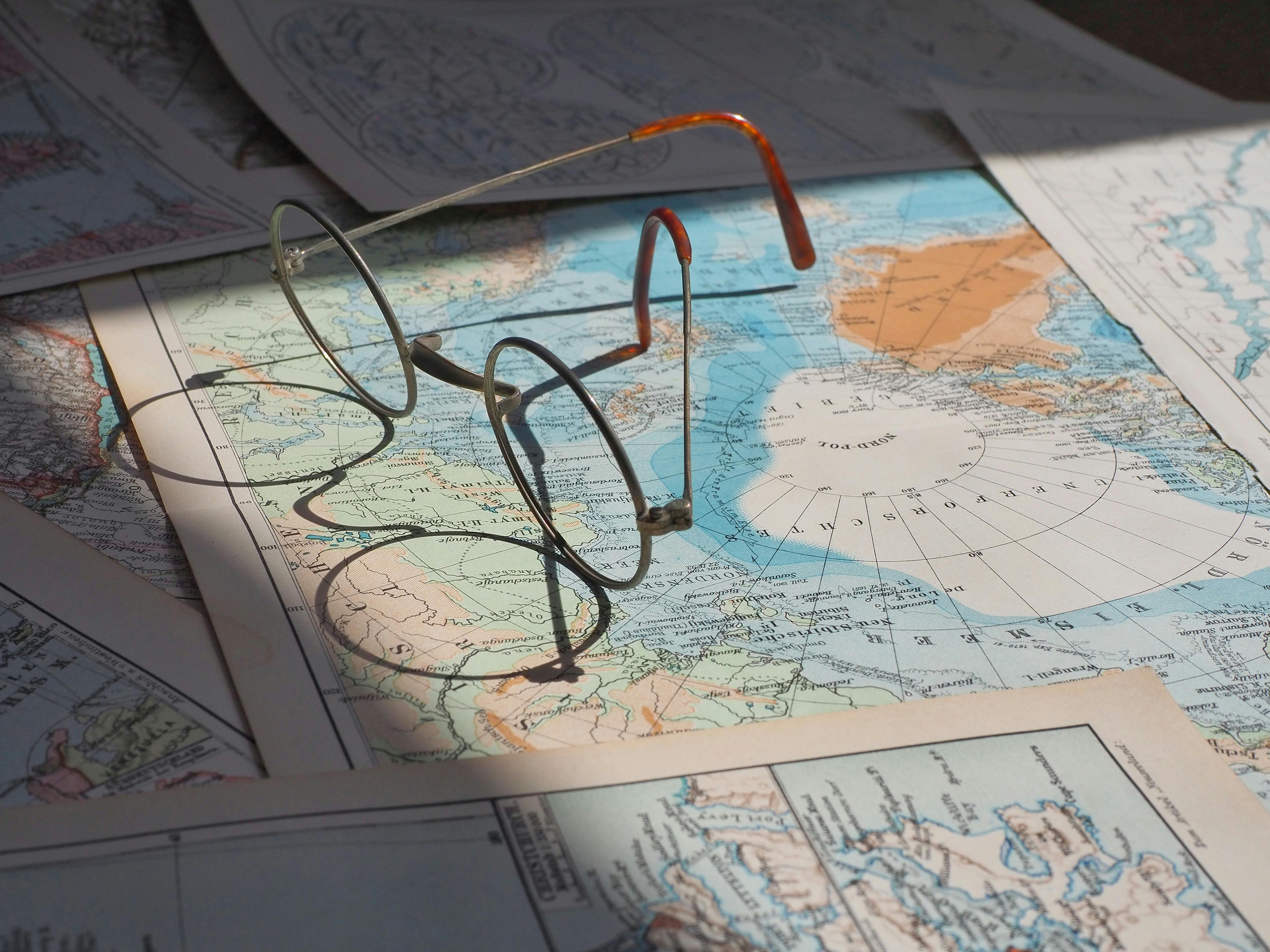 Close-up of Eyeglasses Lying on Maps · Free Stock Photo