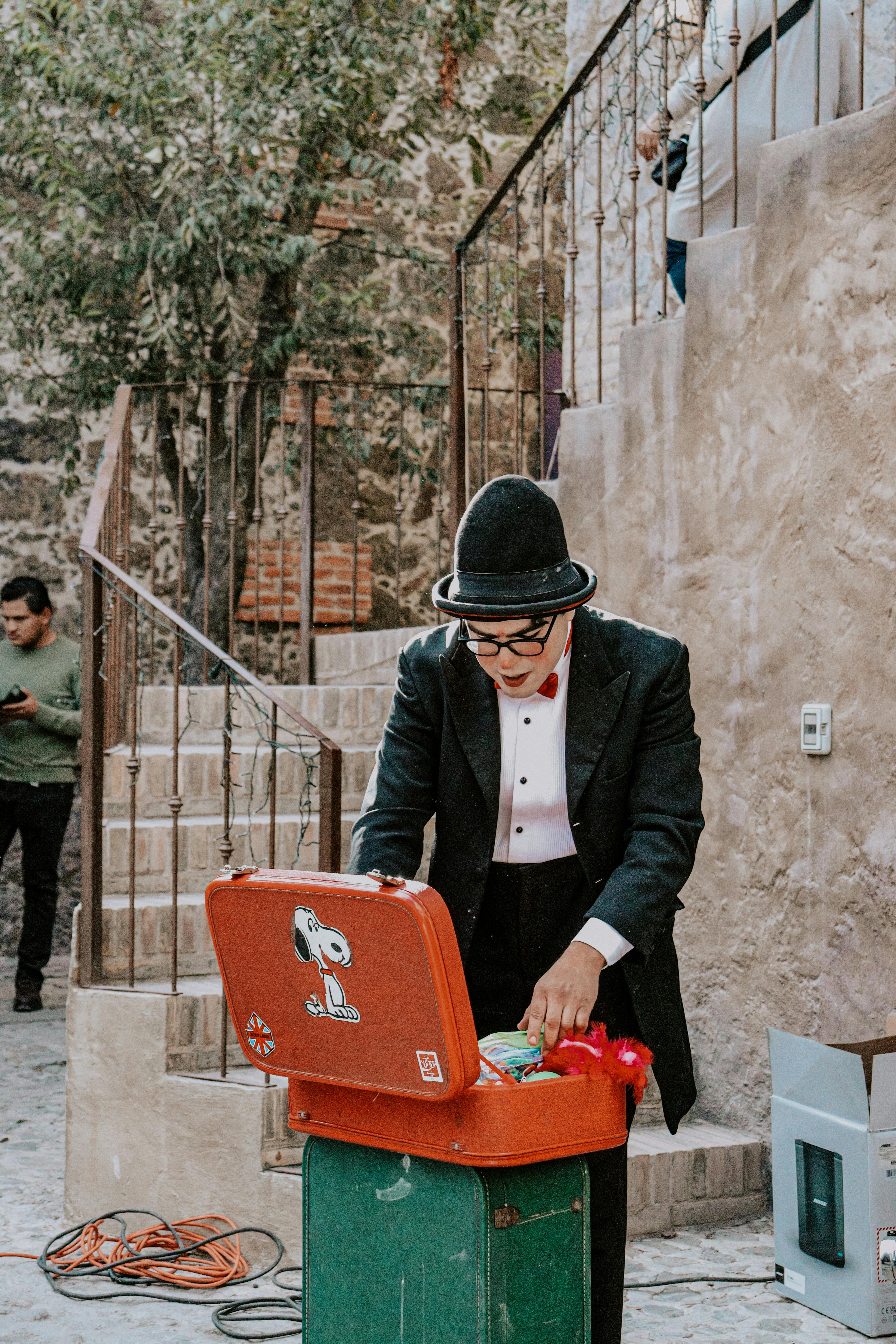 Street Performer Looking Through Props in a Suitcase · Free Stock Photo