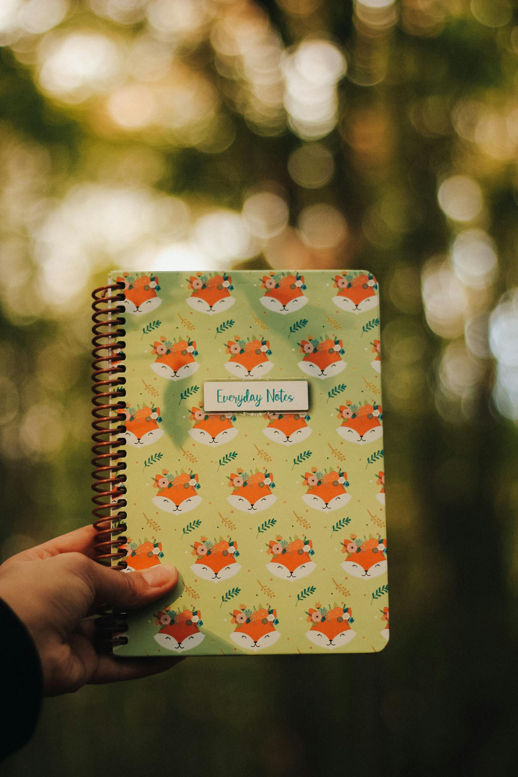 A person holding a notebook with a fox design · Free Stock Photo