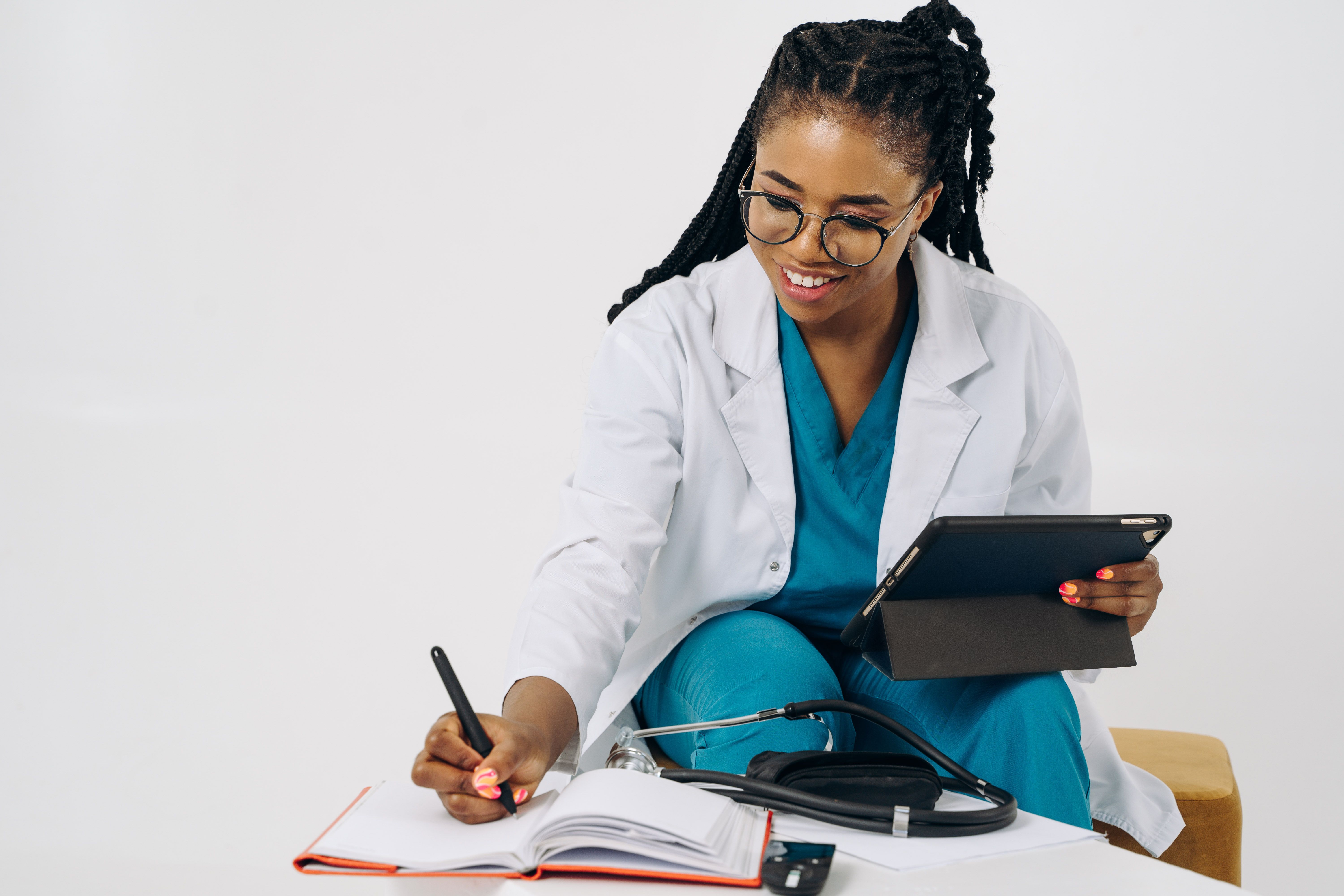 Smiling Black Doctor with Pad Writing in Notebook · Free Stock Photo