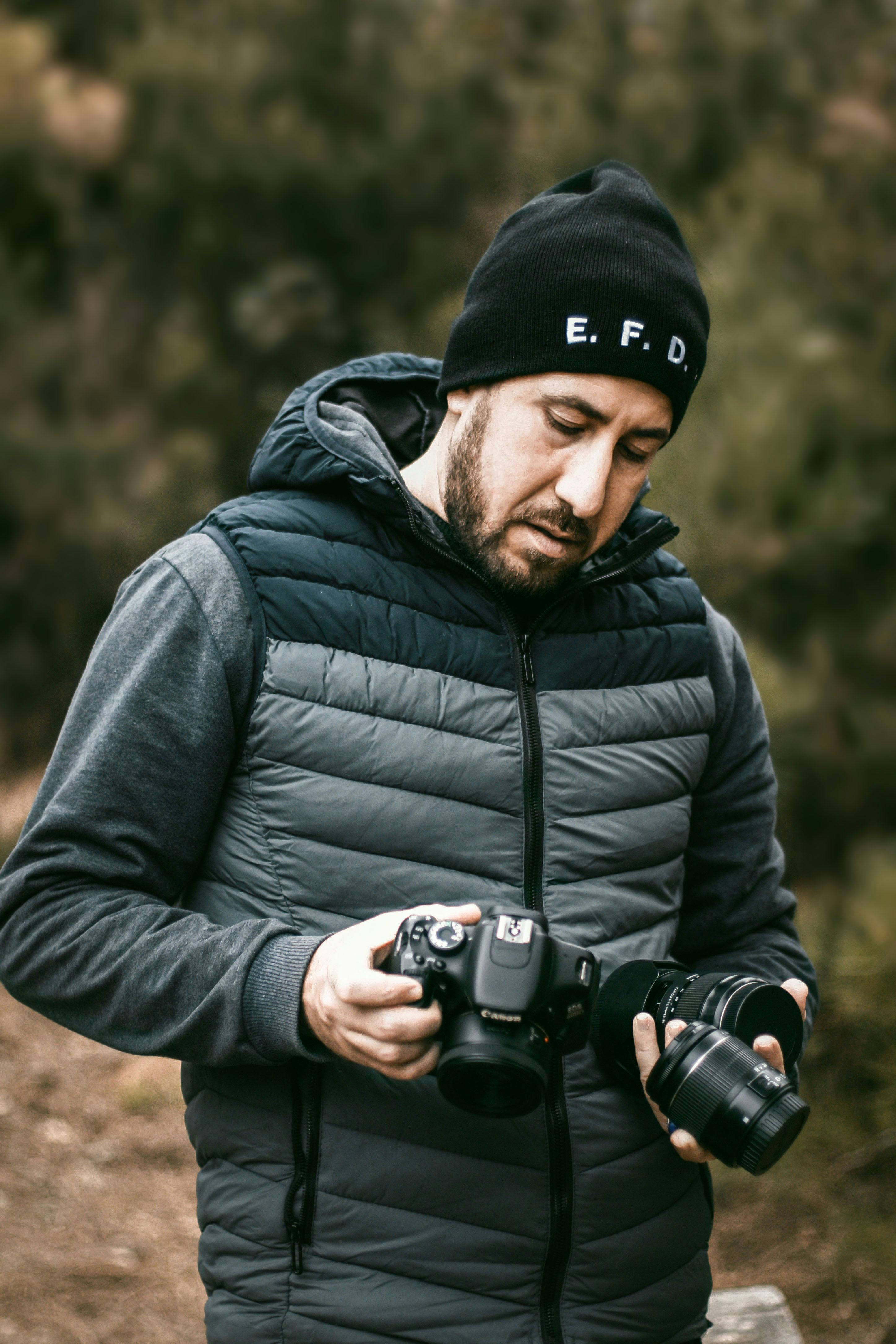 Man in Jacket Standing with Cameras · Free Stock Photo