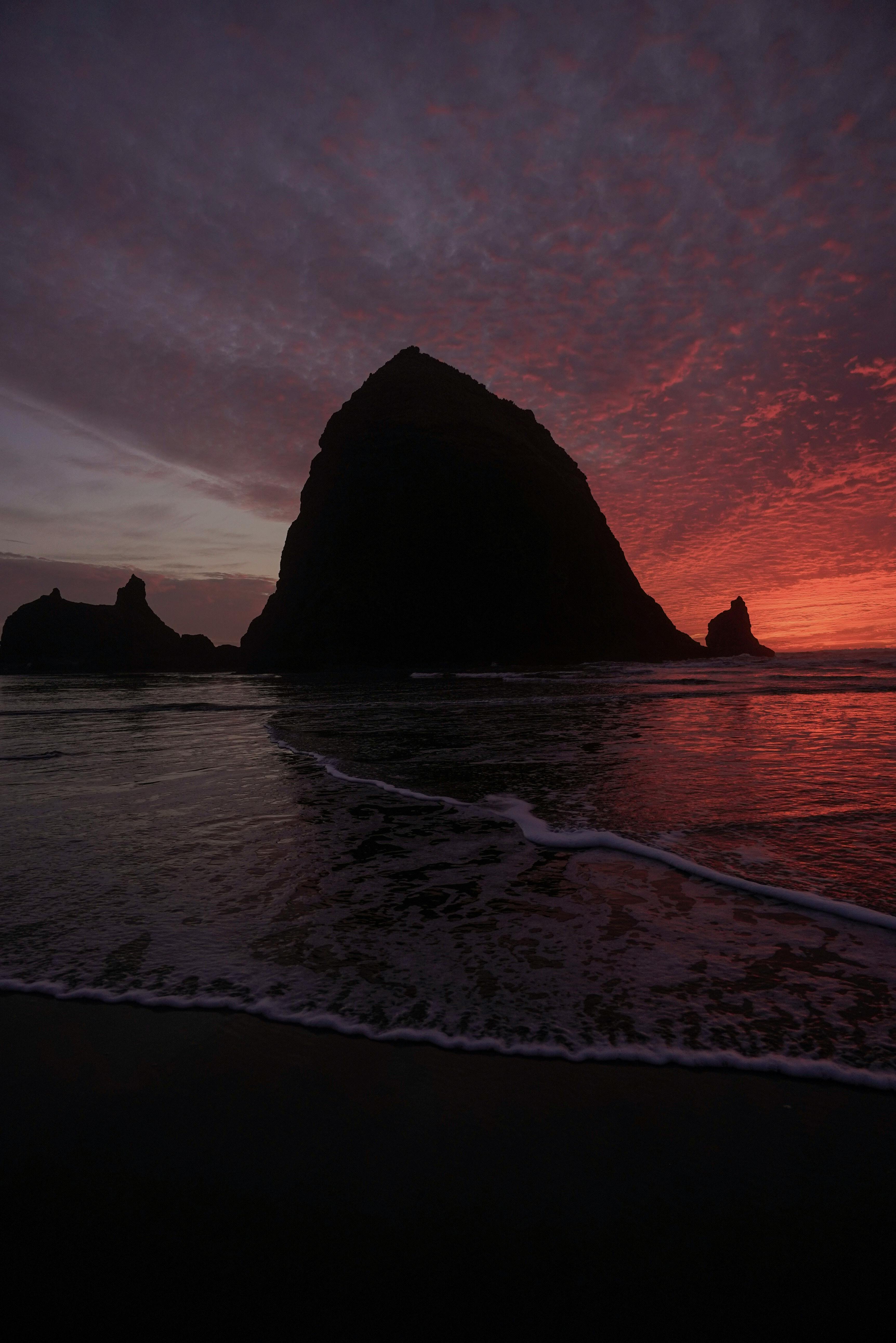 Empty sandy ocean beach and Haystack Rock · Free Stock Photo
