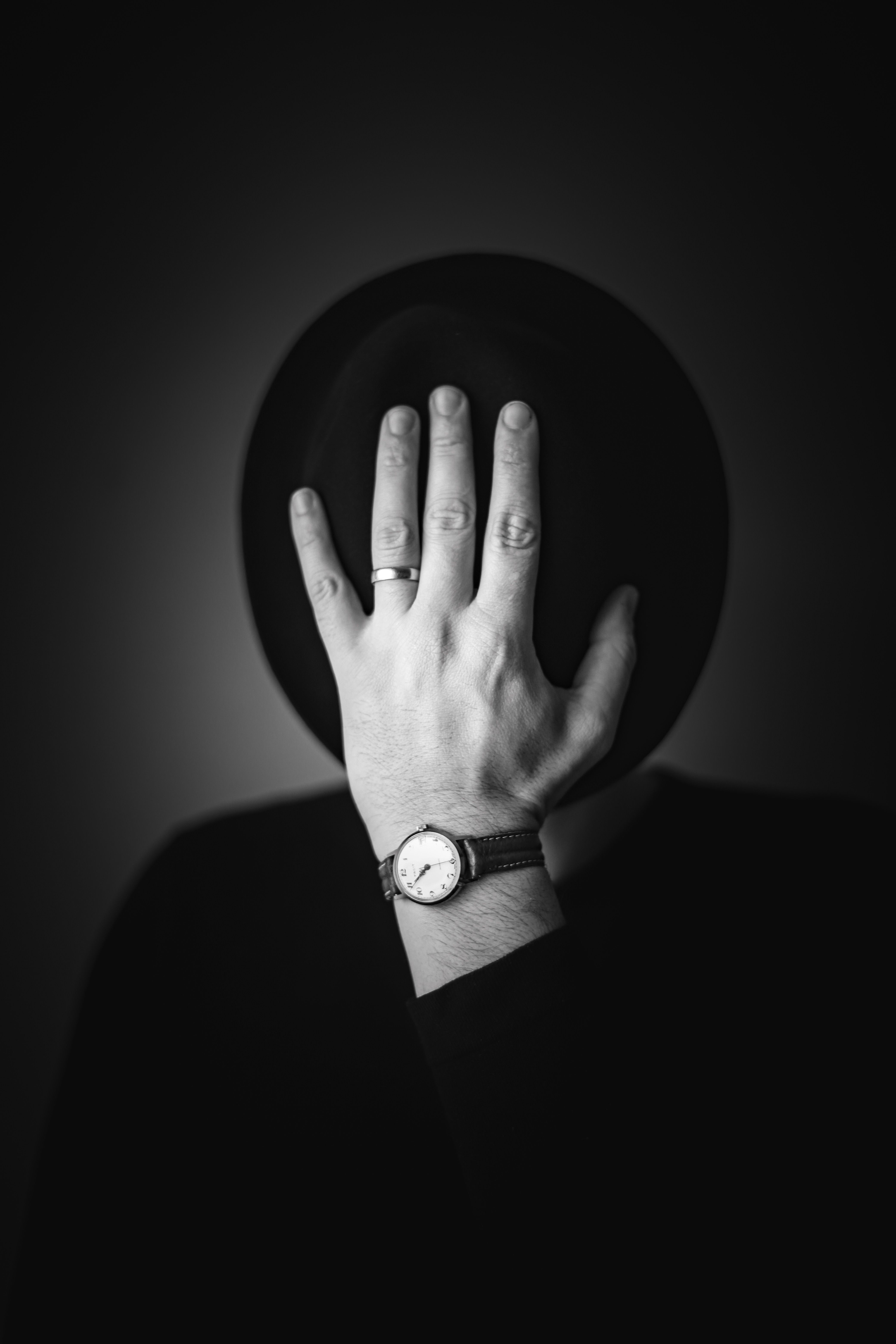 Person with Watch On Hand Holding Hat Over Face · Free Stock Photo