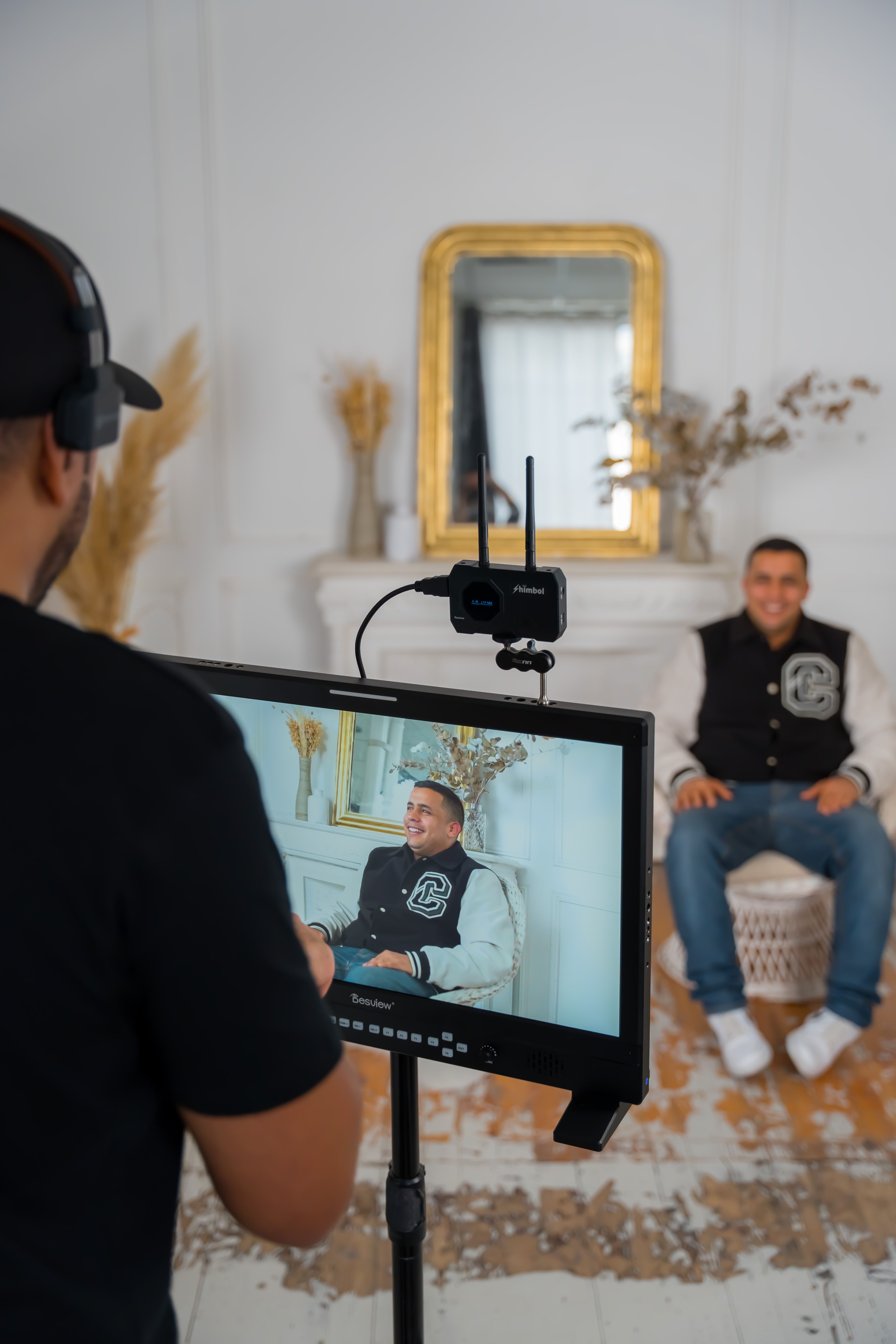 Photographer Recording Man Sitting and Smiling in Room · Free Stock Photo