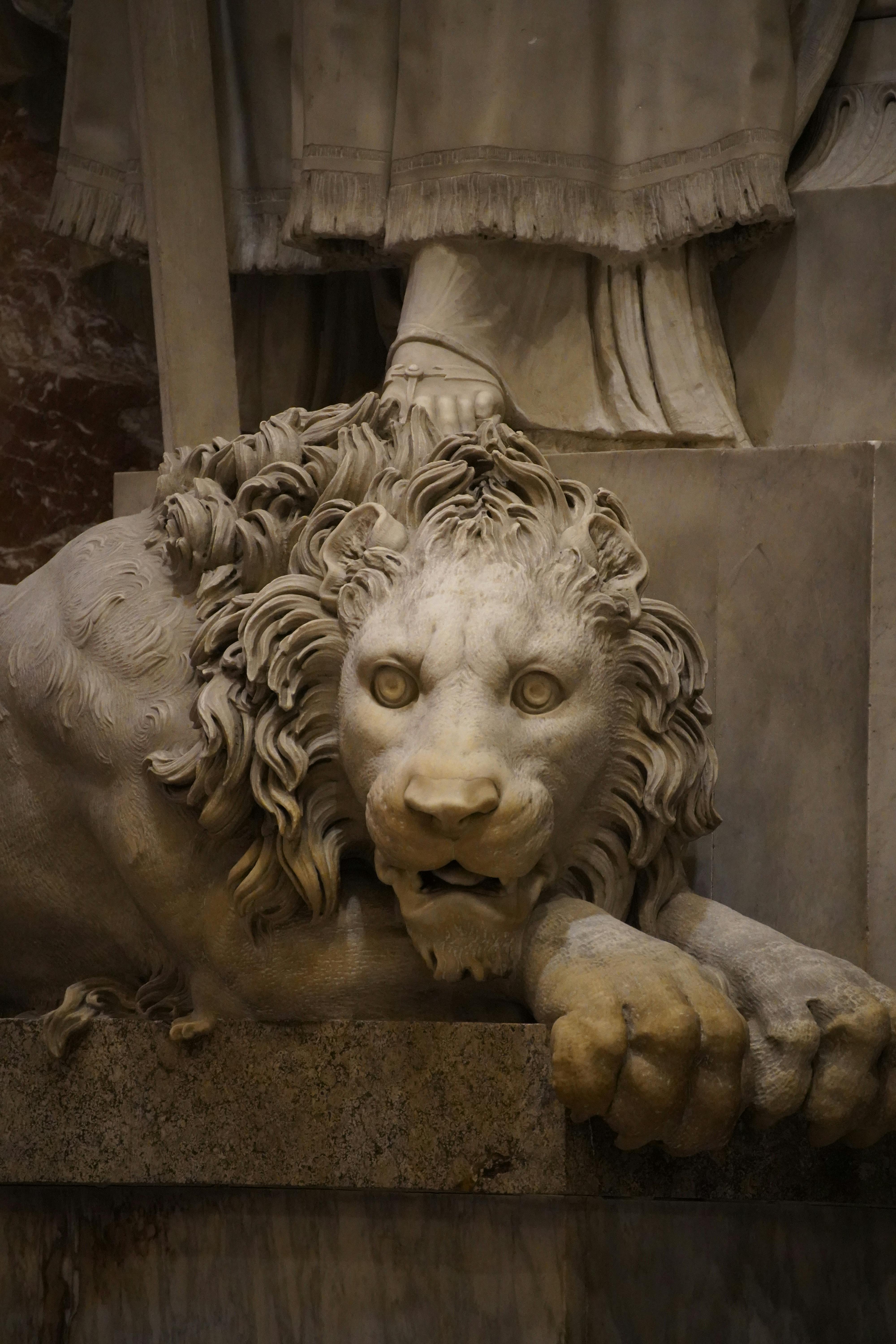 A statue of a lion with its head resting on a stone · Free Stock Photo