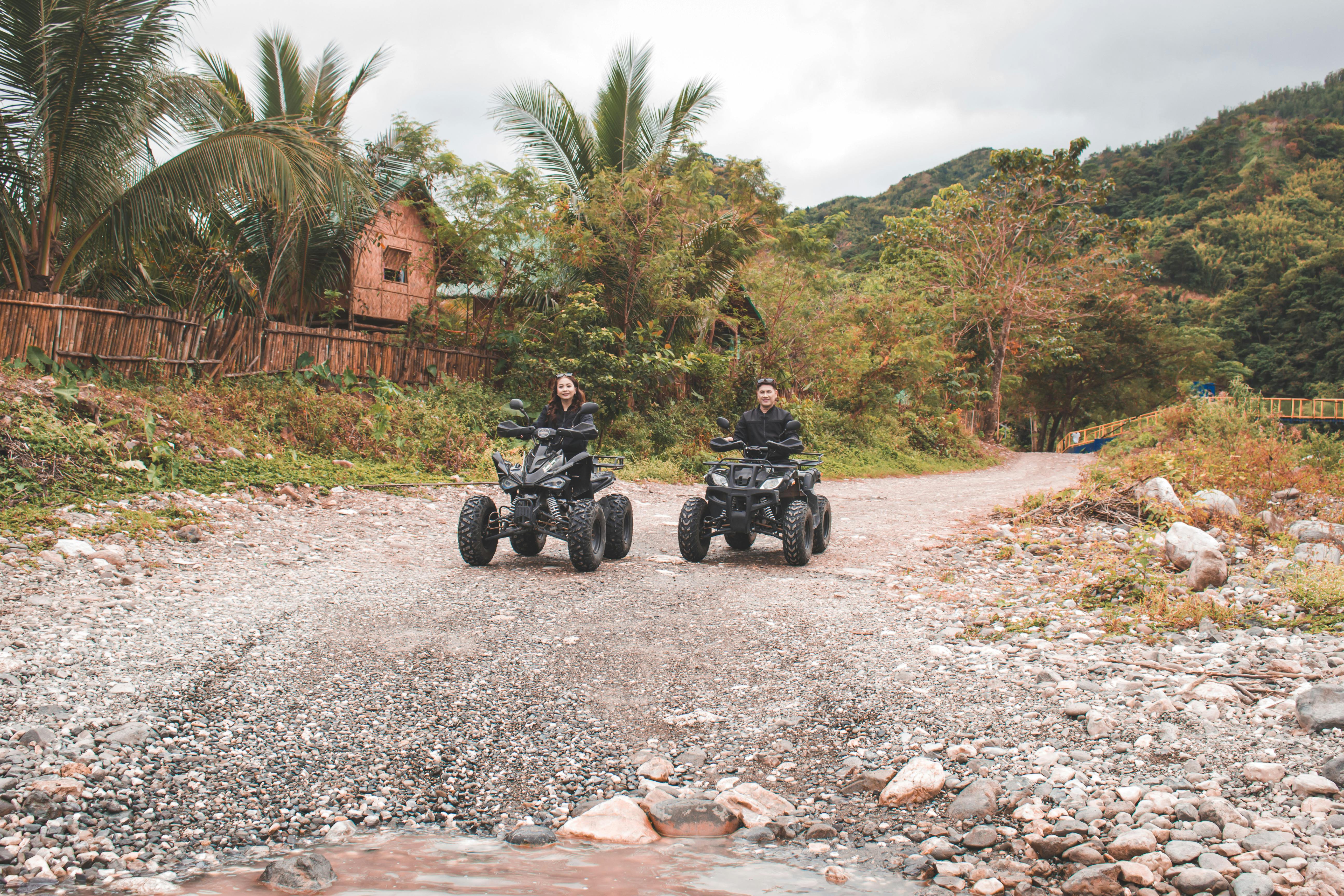 Couple Riding Quad Bikes on a Gravel Country Road · Free Stock Photo