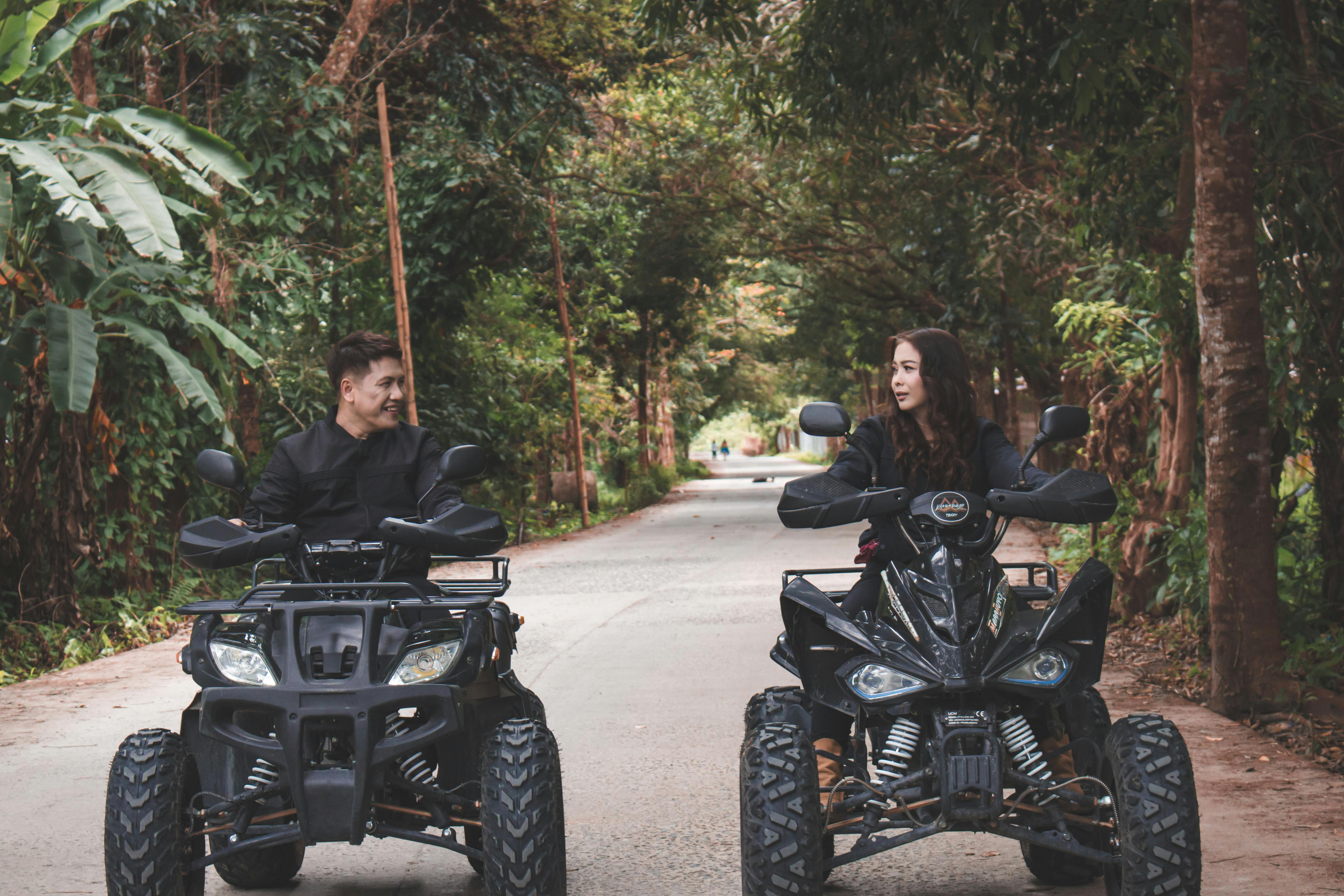 Two people riding atvs on a road · Free Stock Photo