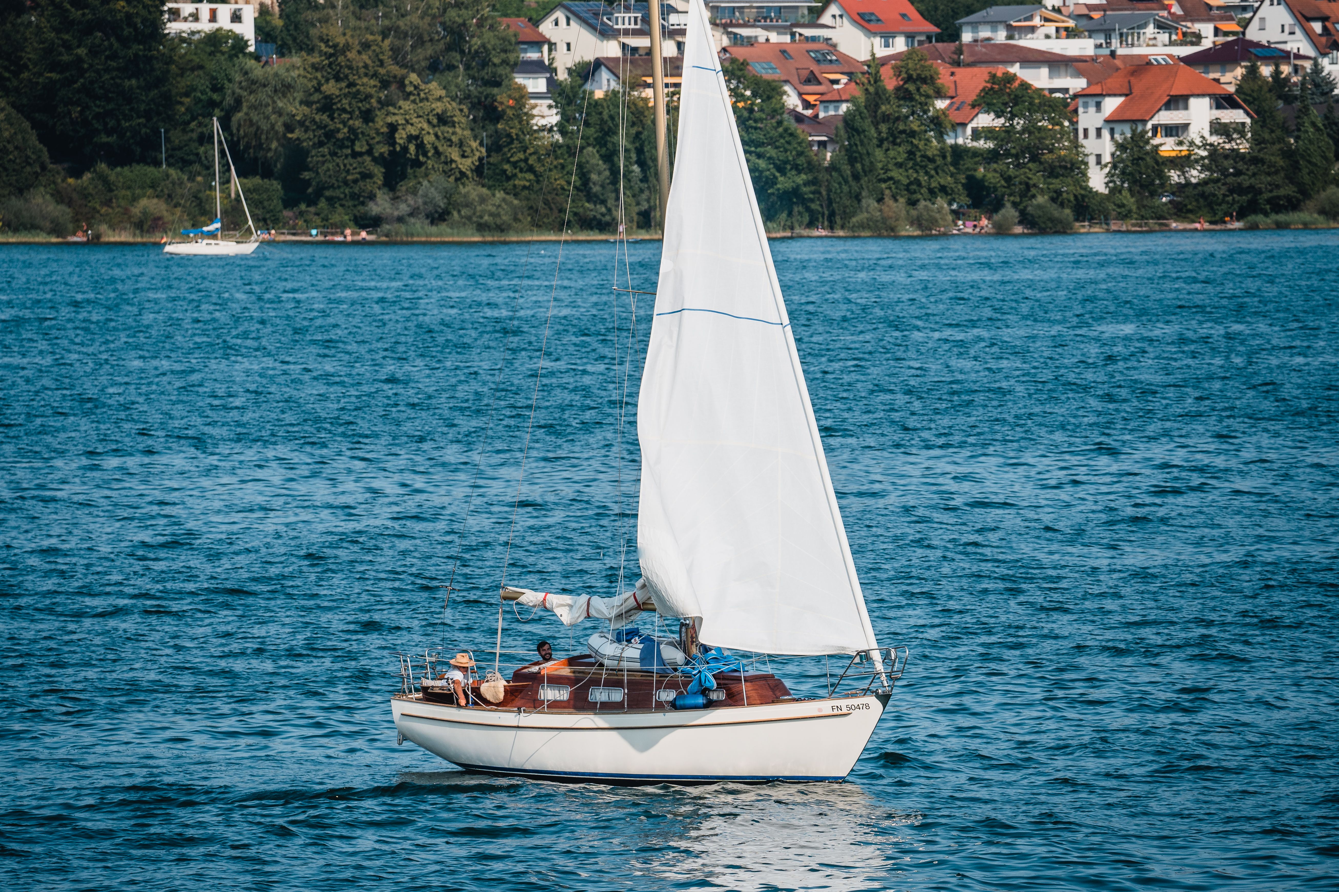 People Sailing on Sailboat on Lake in Town · Free Stock Photo