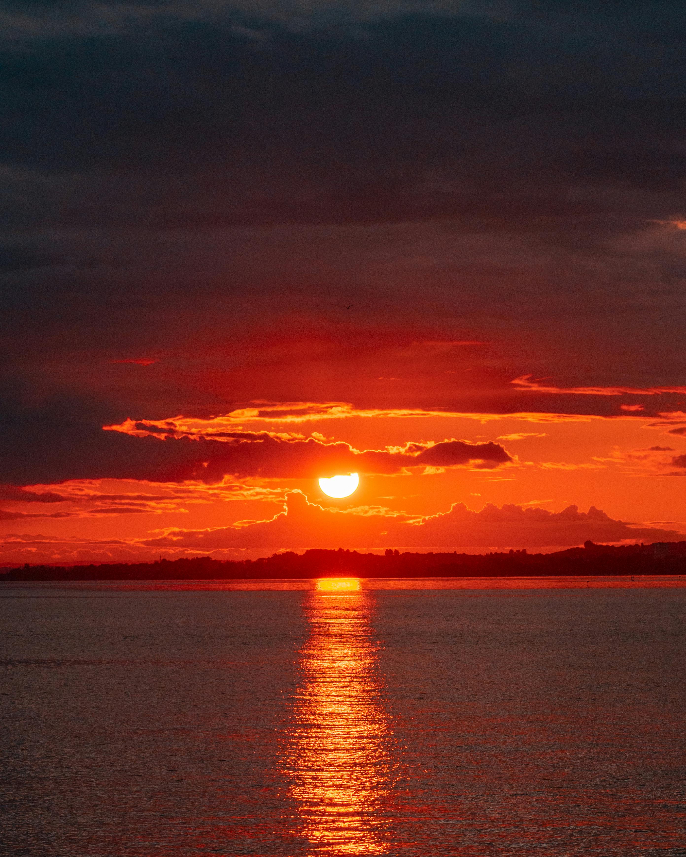 A red sun setting over the water · Free Stock Photo