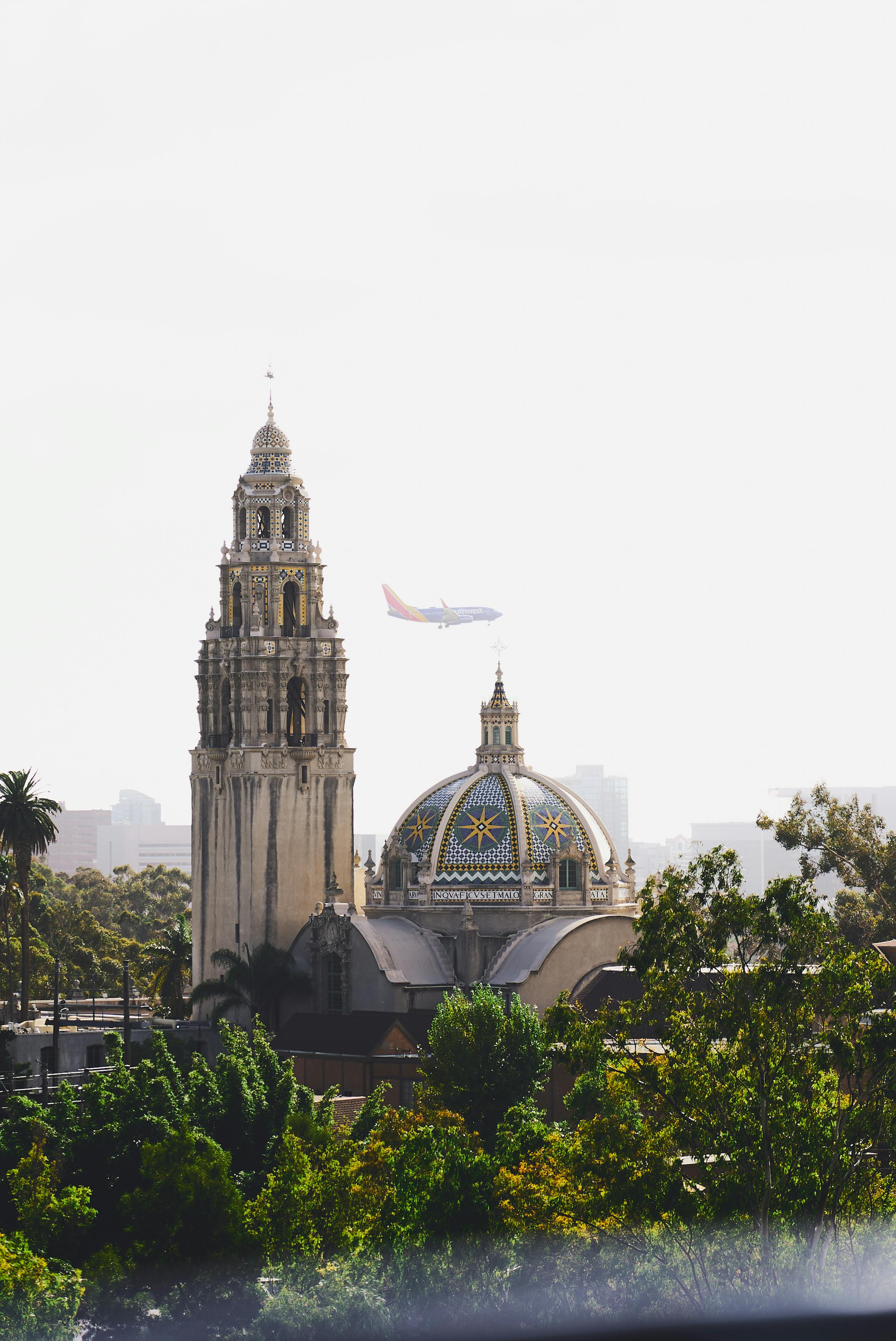 A plane flying over a church and a building · Free Stock Photo