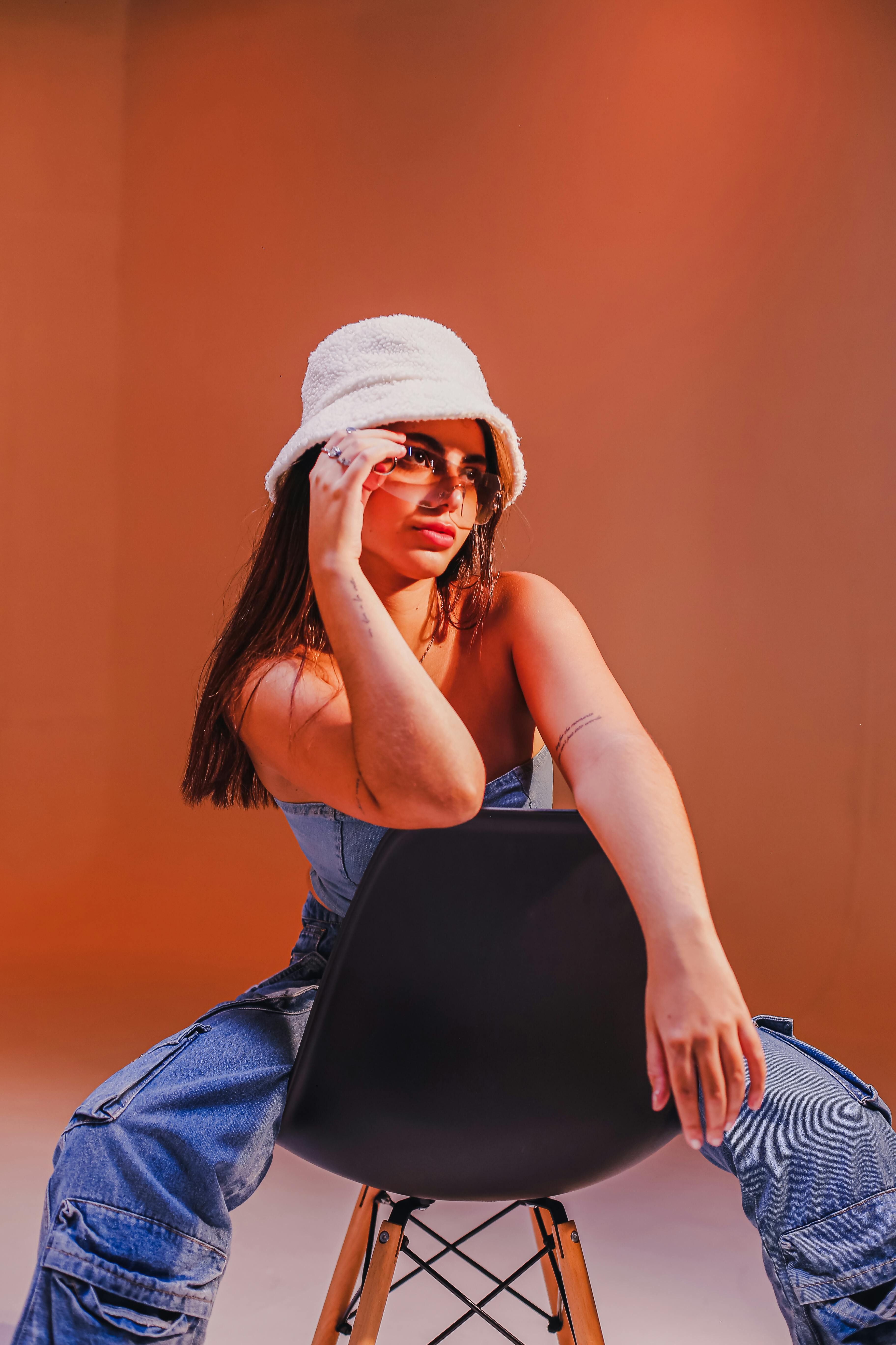 A woman in overalls sitting on a chair · Free Stock Photo