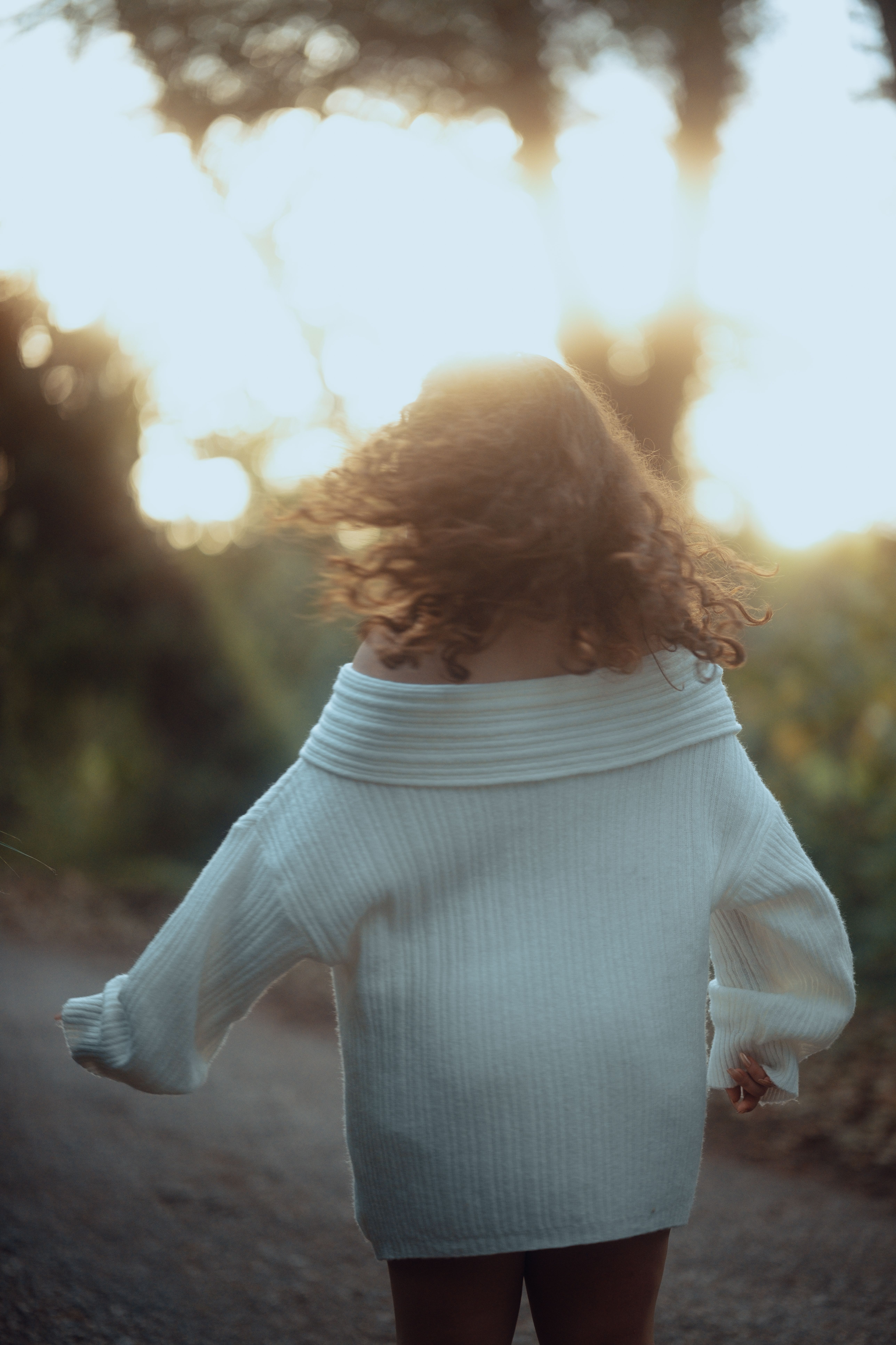 Back View of a Woman in a White Sweater Walking Outside at Sunset ...
