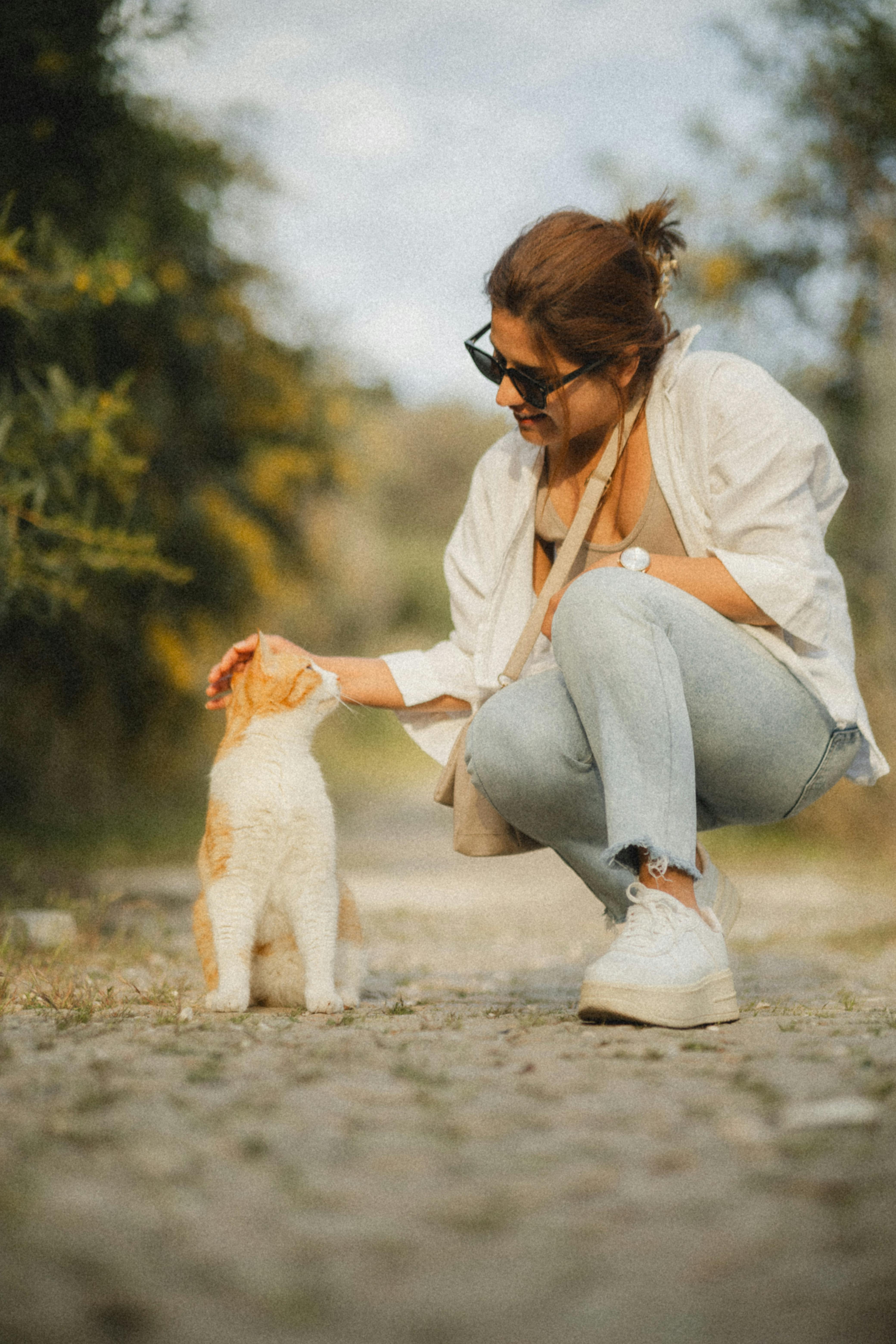 Woman Crouching and Patting Cat on Pavement · Free Stock Photo