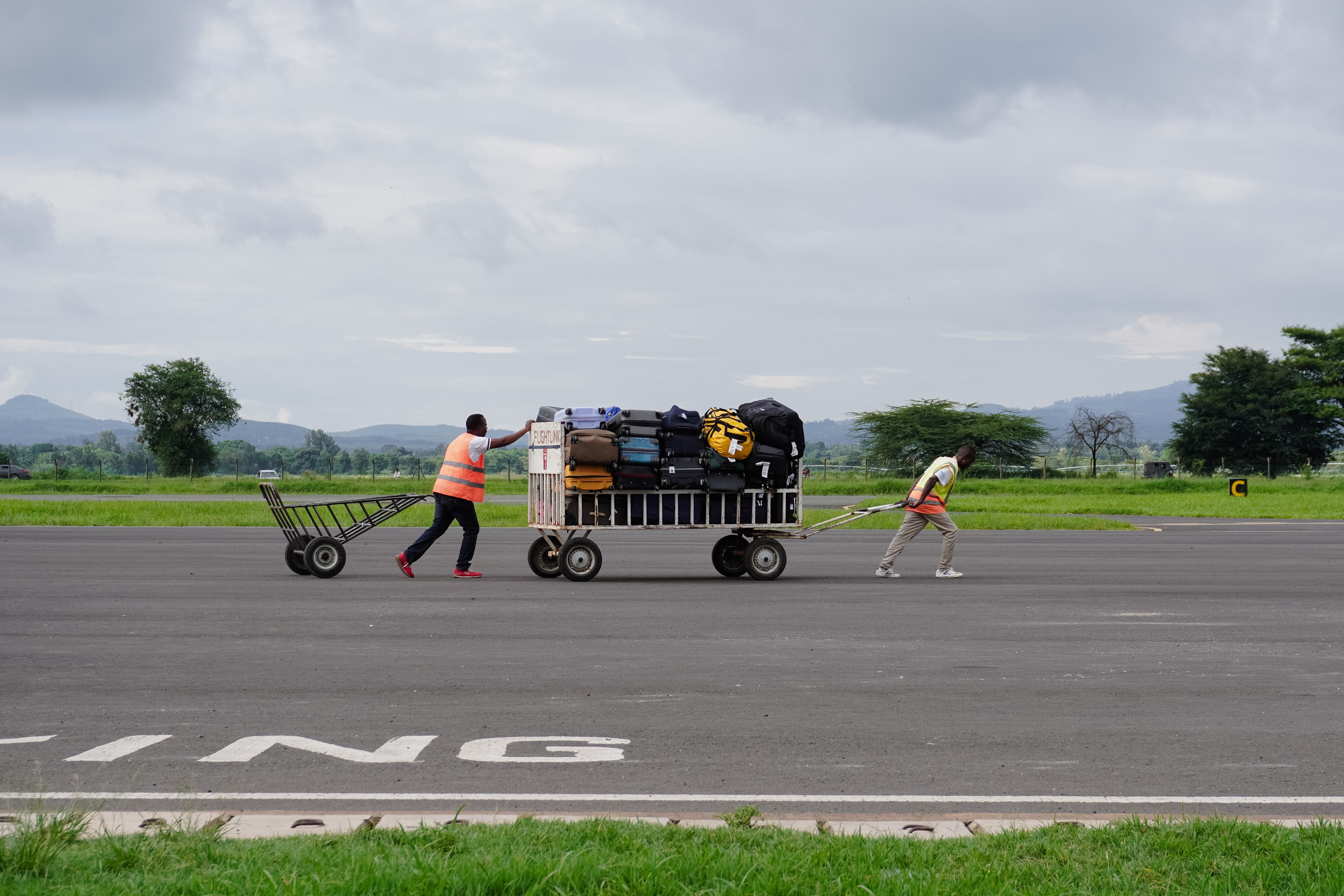 Men Towing Trailer with Baggage on Airport Tarmac · Free Stock Photo