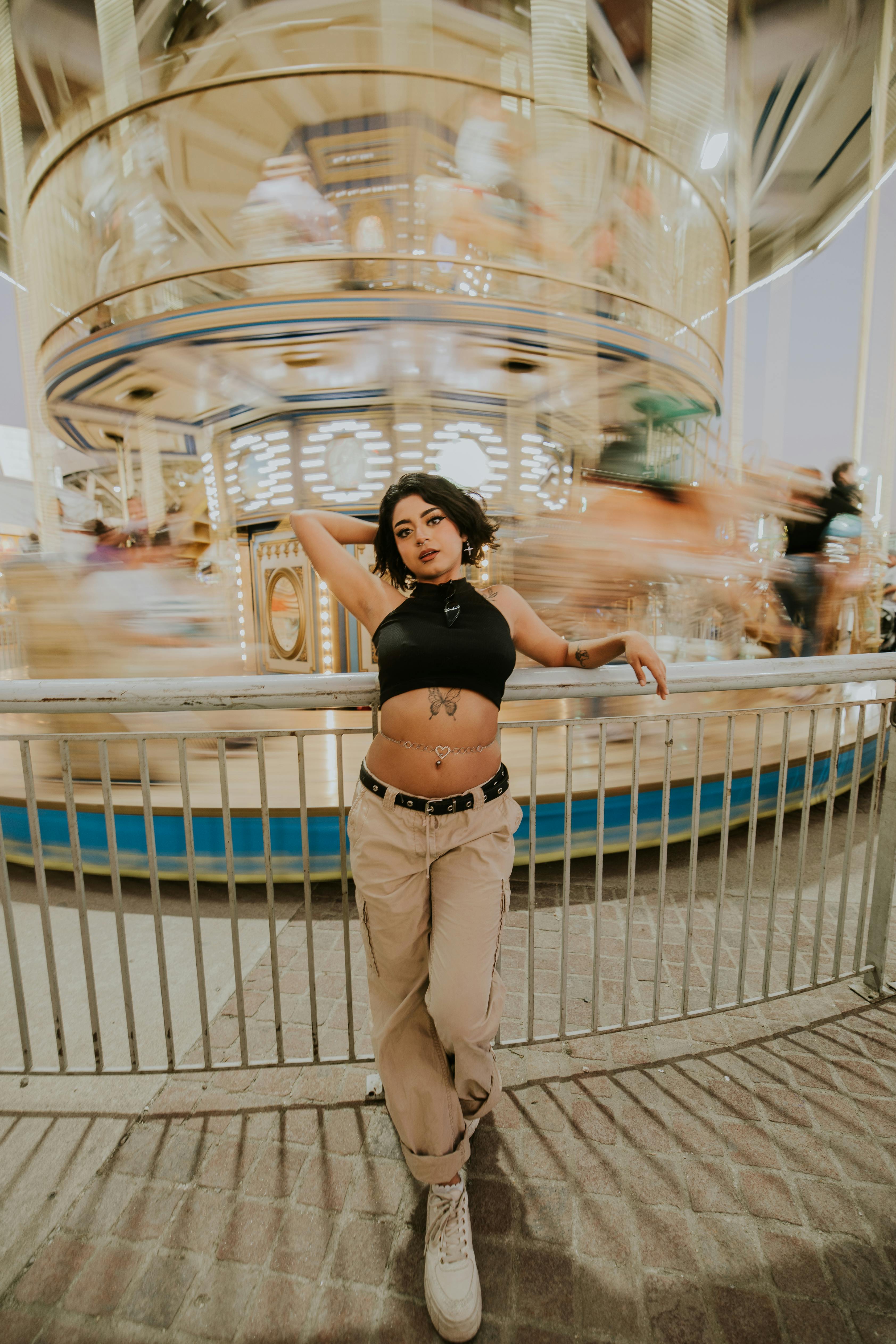 Female Model Leaning on a Railing in Front of a Spinning Carousel ...