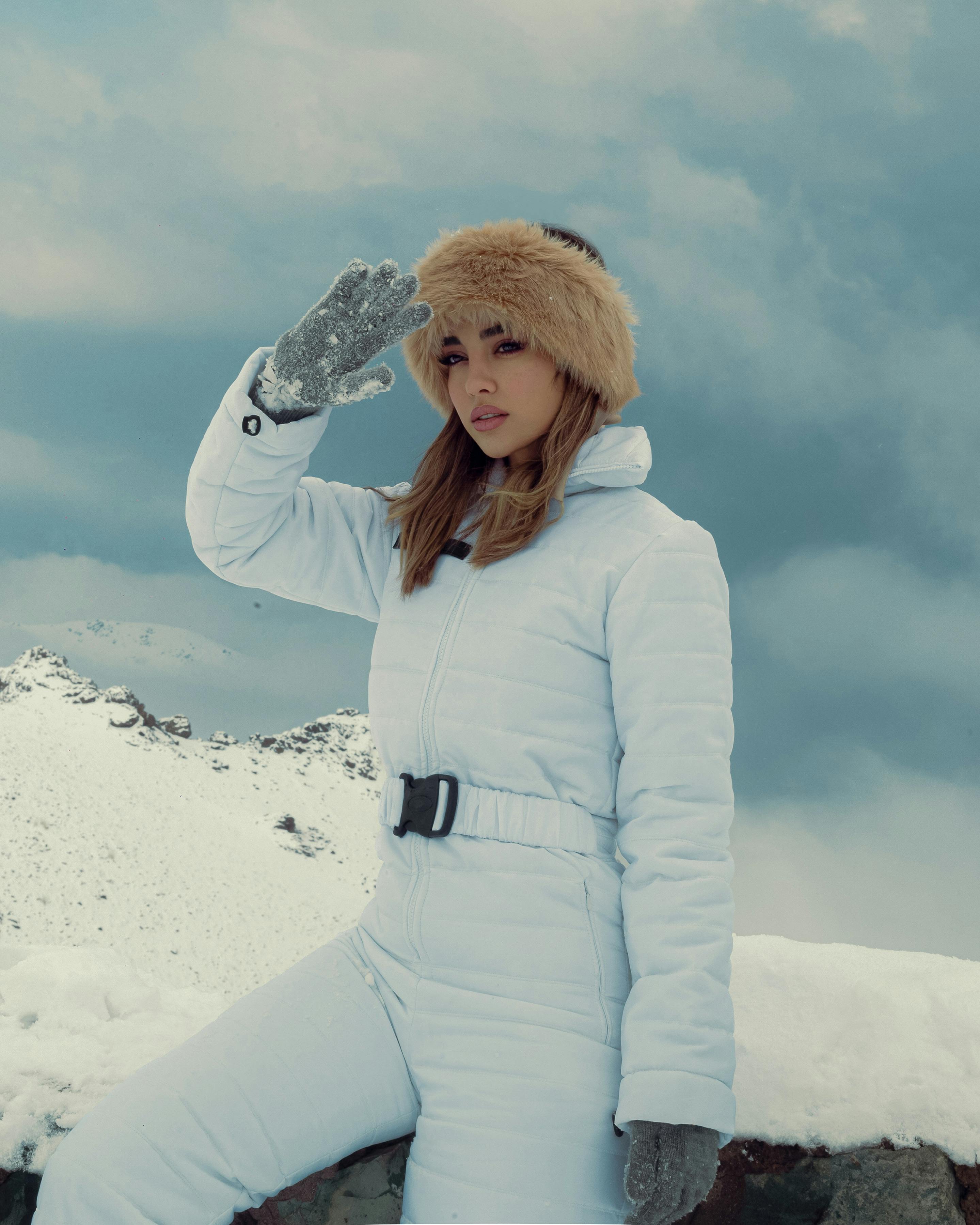 A woman in a white snow suit standing on a rock · Free Stock Photo