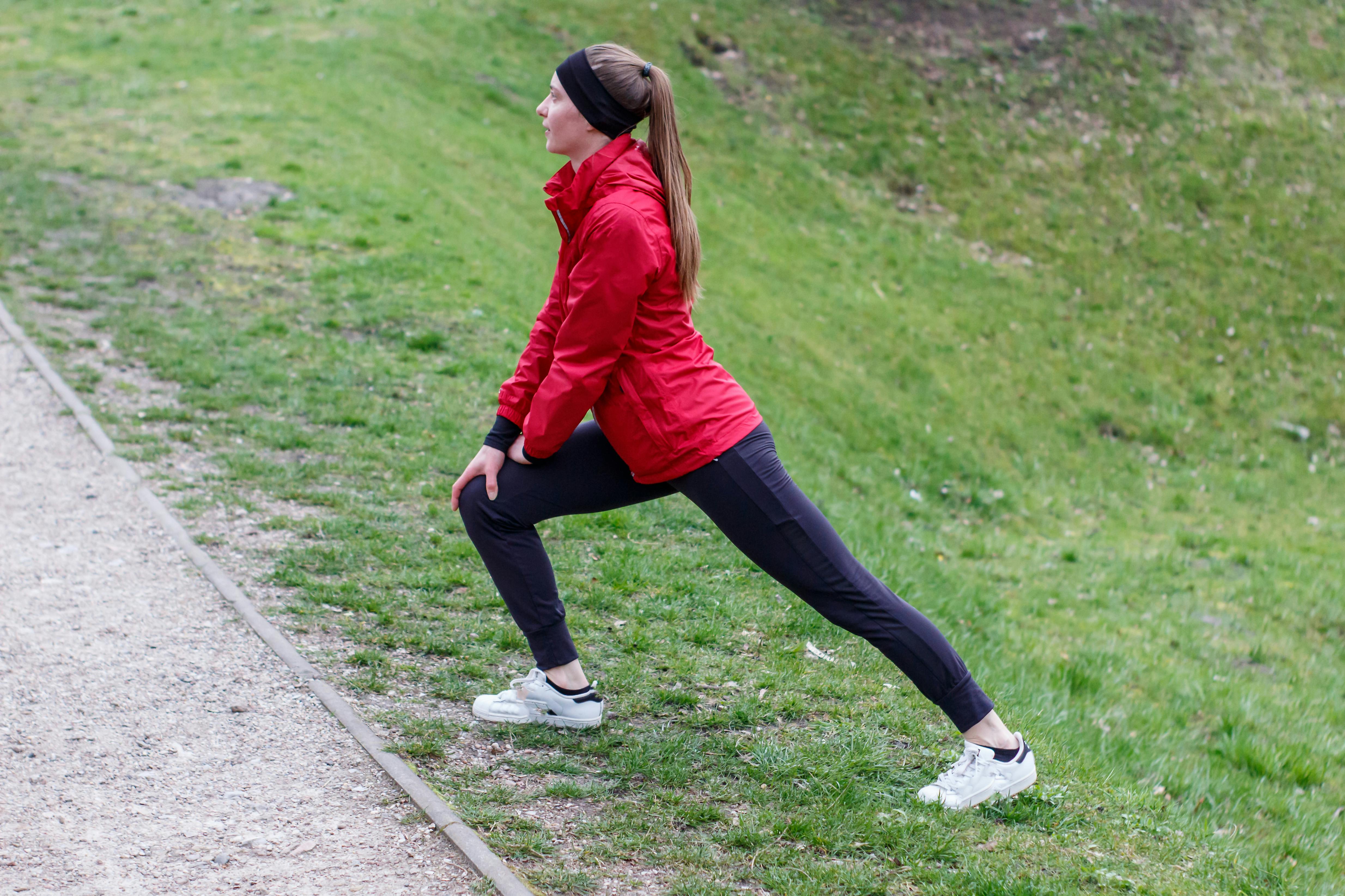 Active Woman in Red Jacket Stretching in Park · Free Stock Photo
