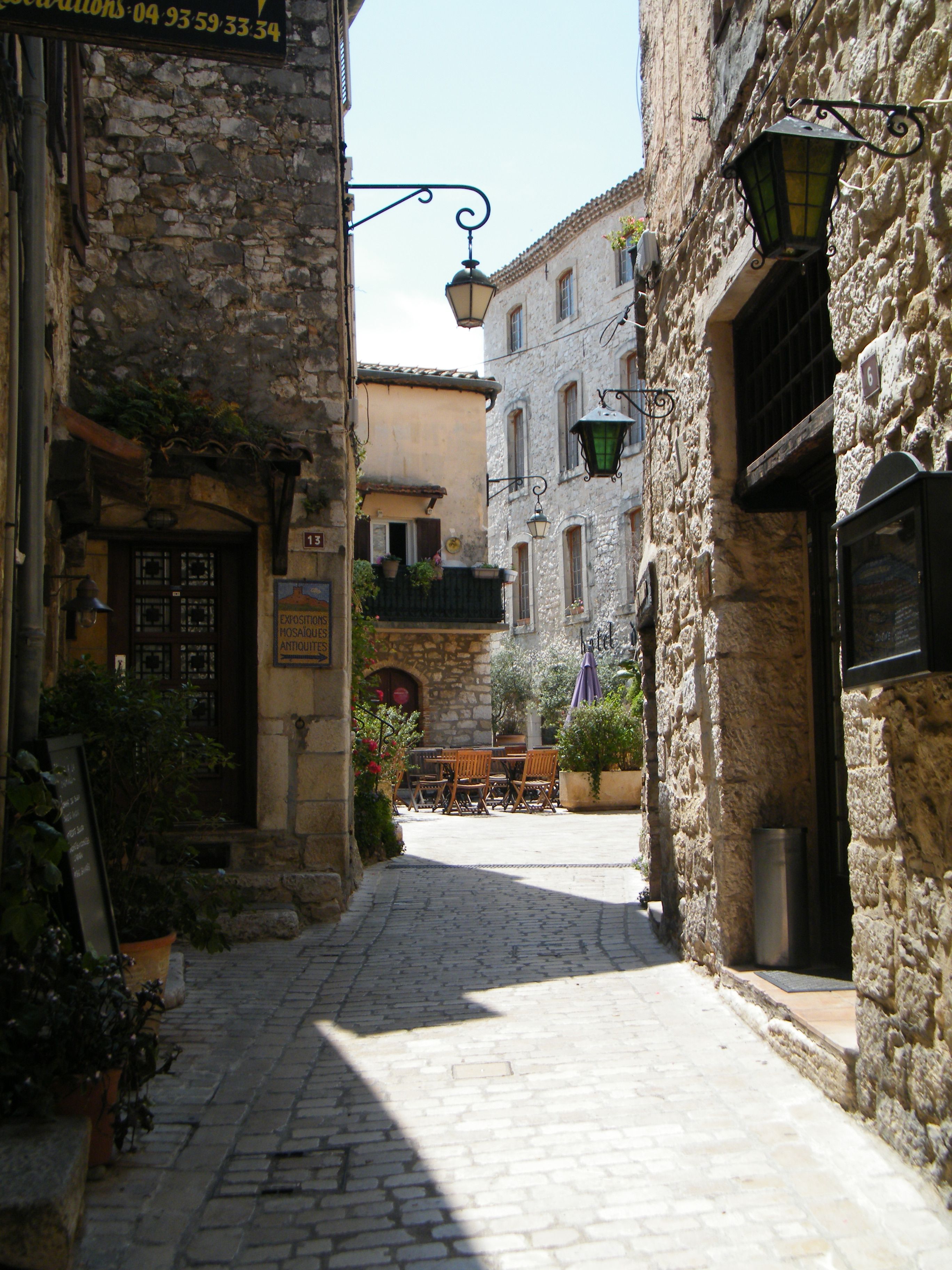 A narrow alley with stone buildings and tables · Free Stock Photo
