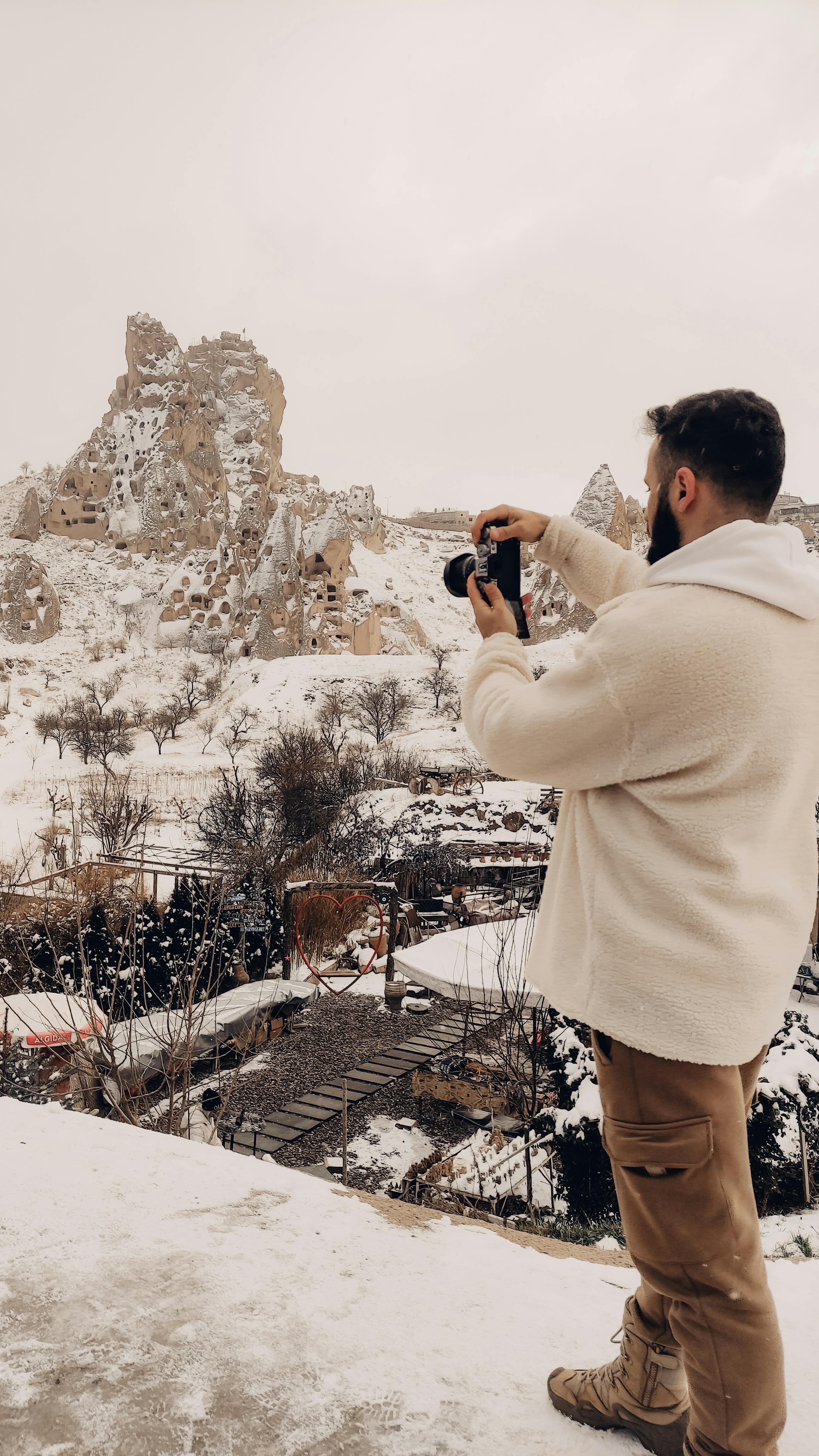 Man Photographing Snow-Covered Hills · Free Stock Photo