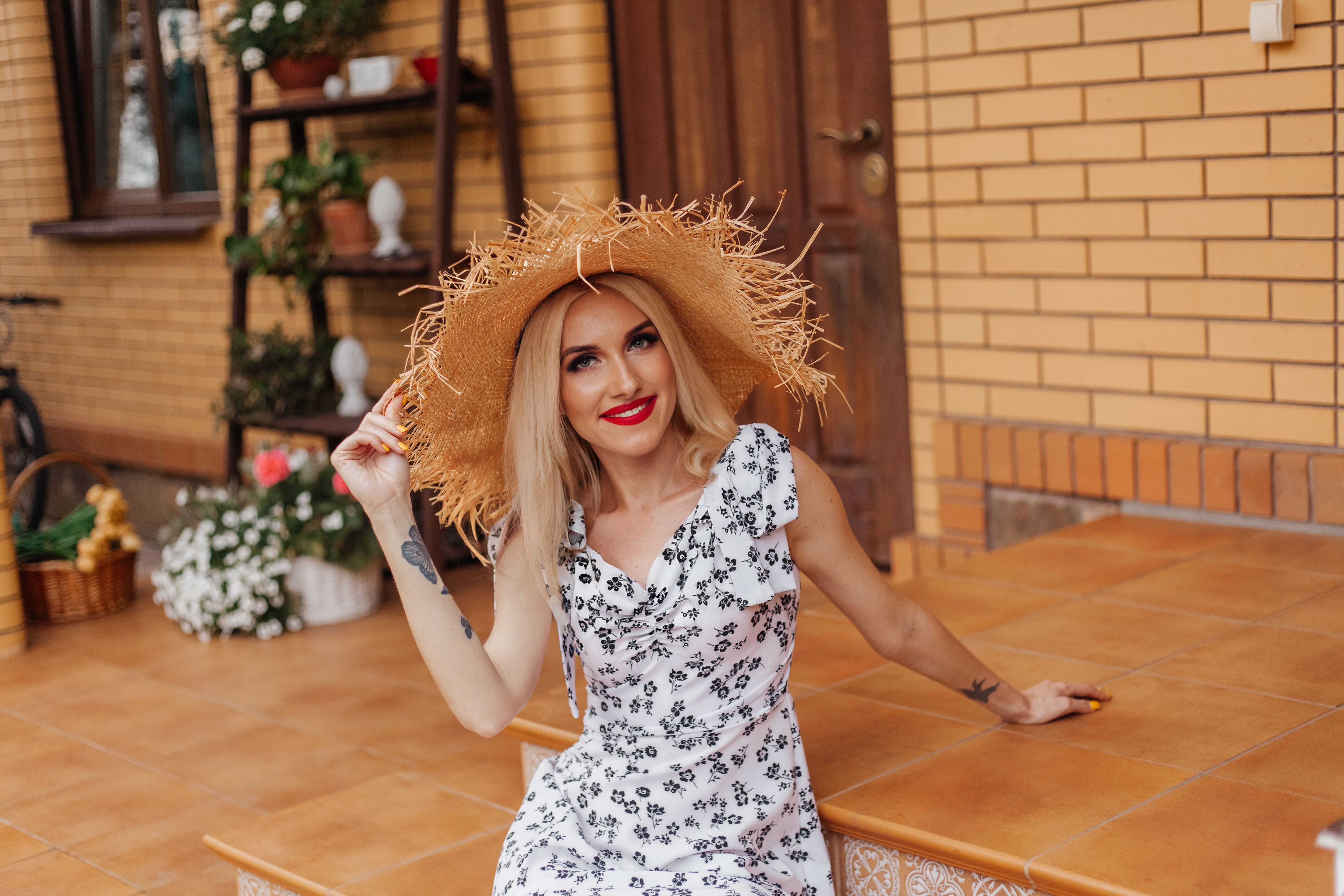 Model in a White Floral Summer Dress and a Straw Hat Sitting on the ...