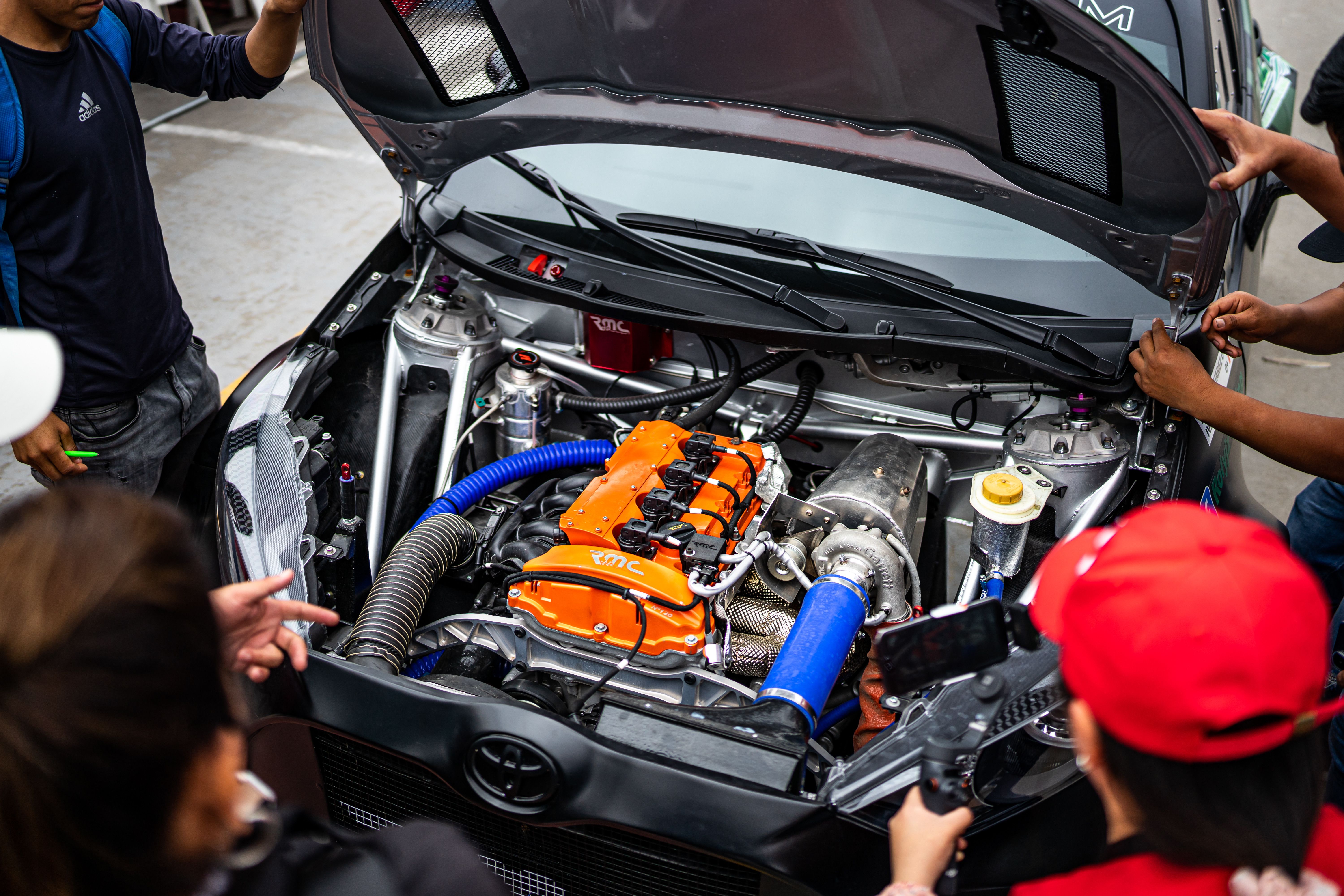 People Standing around Open Hood of Sports Car · Free Stock Photo