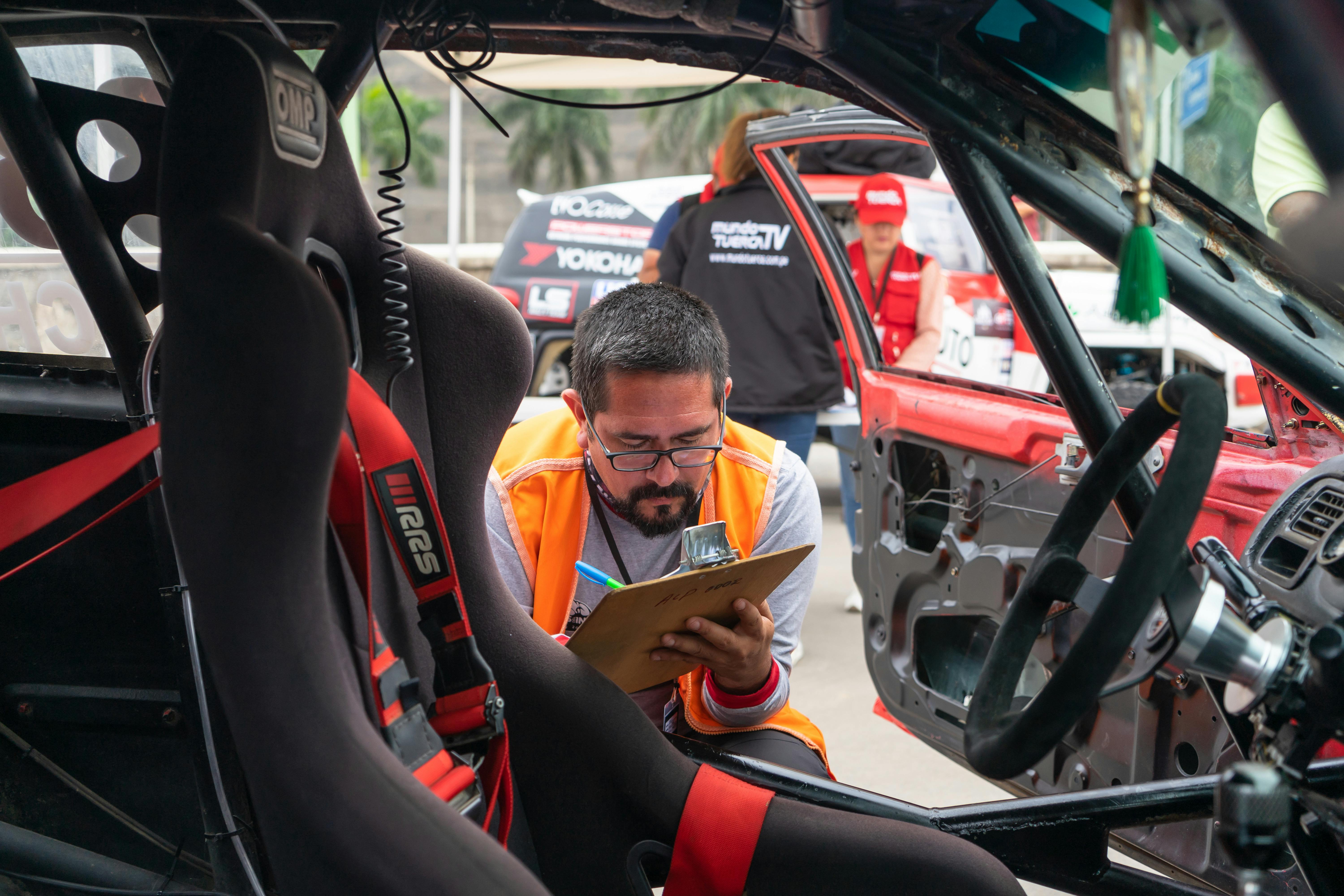 A Man Crouching near a Race Car Writing on a Piece of Paper · Free ...