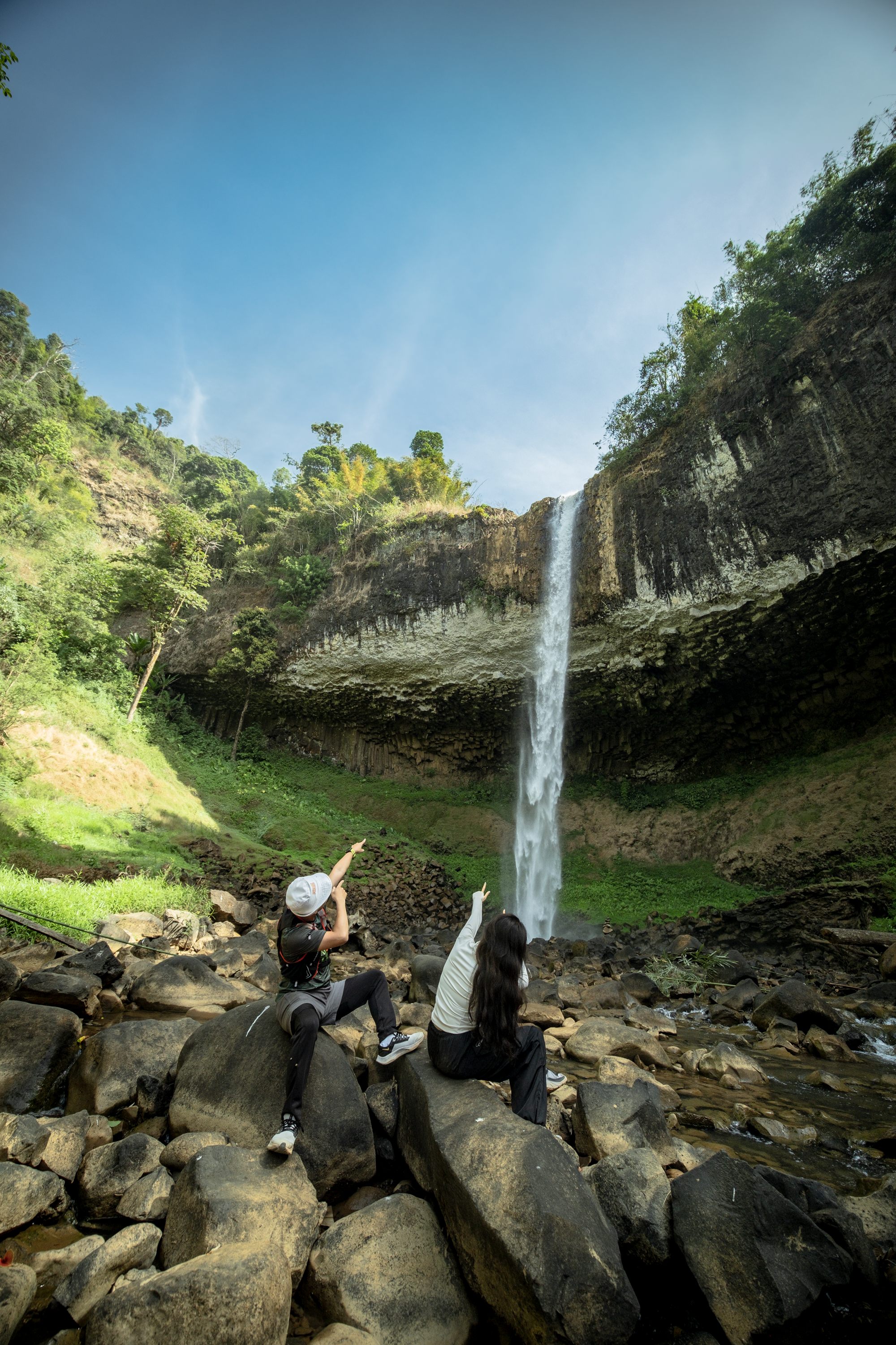 Women Sitting on Rocks under Waterfall · Free Stock Photo