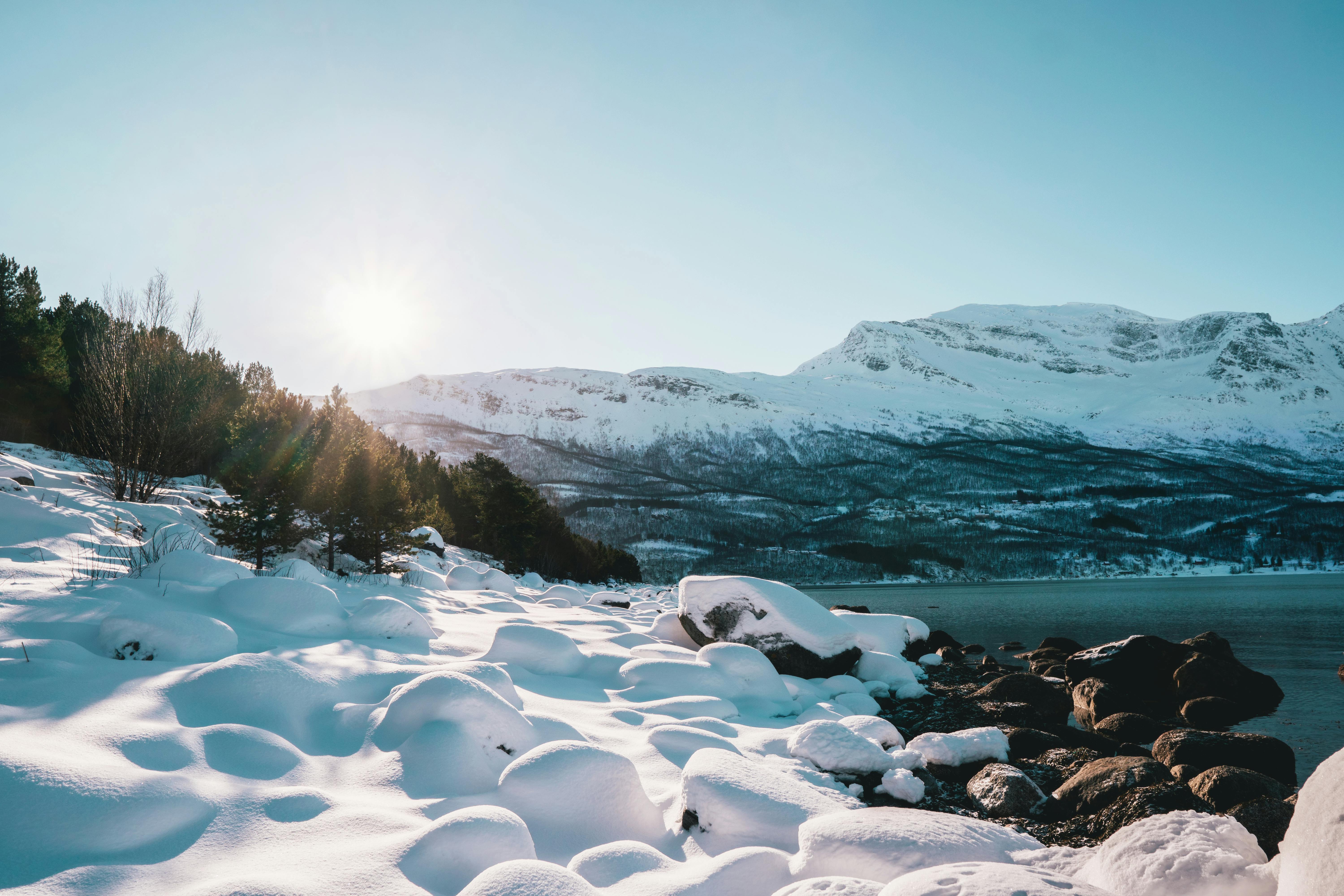 Snow Covered Rocks on Shore Near Hill · Free Stock Photo
