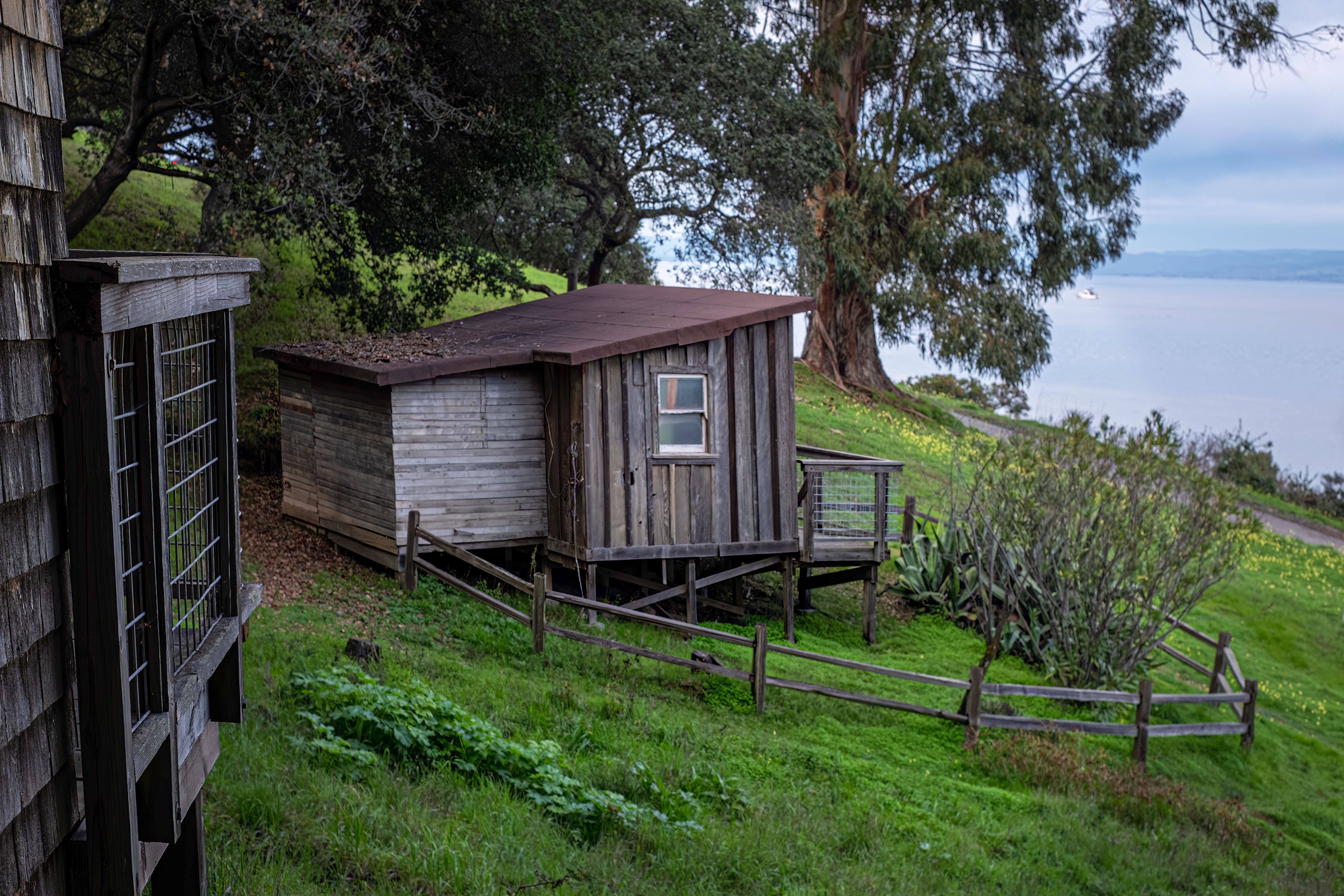 A small cabin sits on a hillside overlooking the ocean · Free Stock Photo