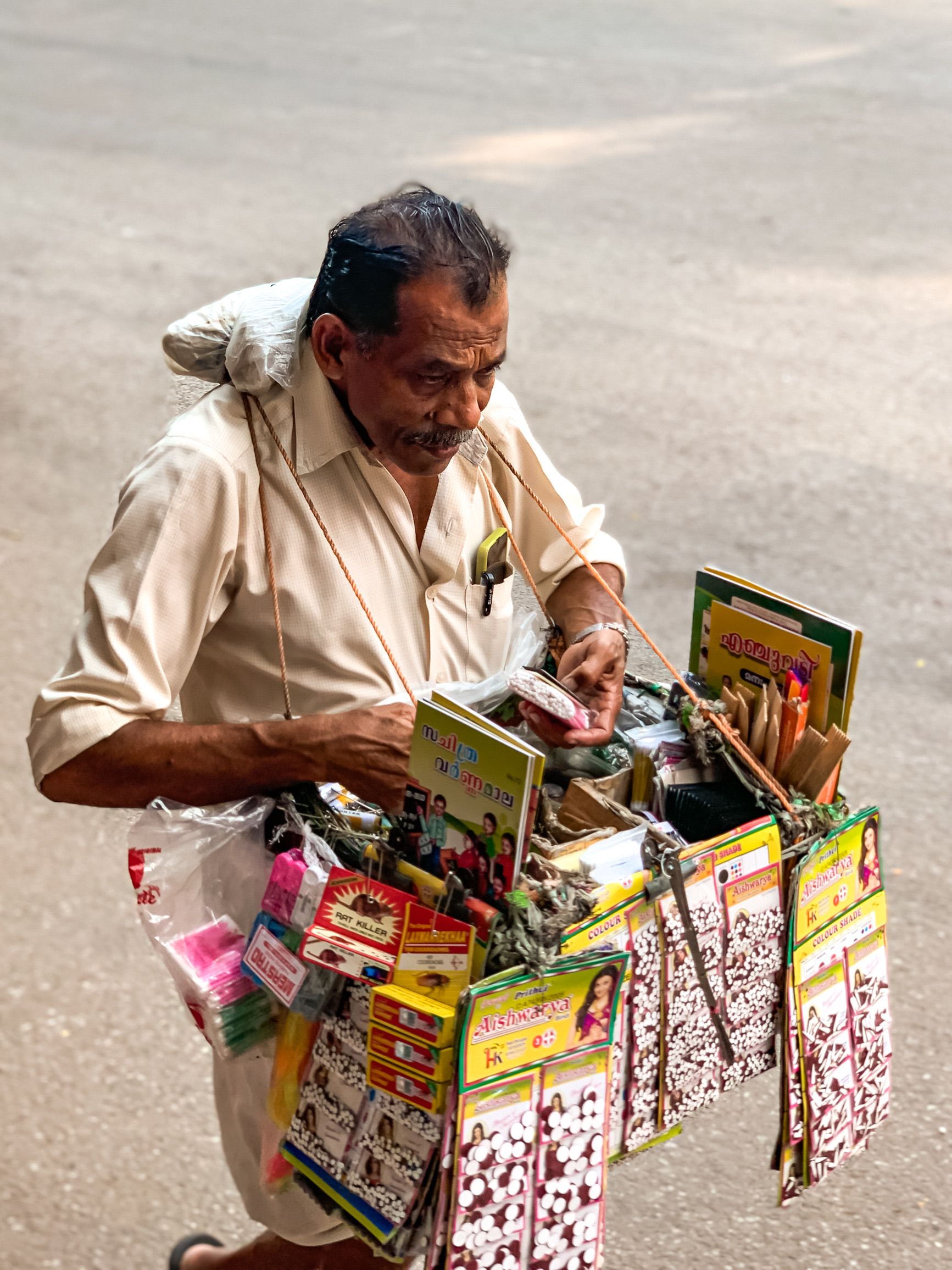 A Man Selling Books and Toys Walking on a Street · Free Stock Photo