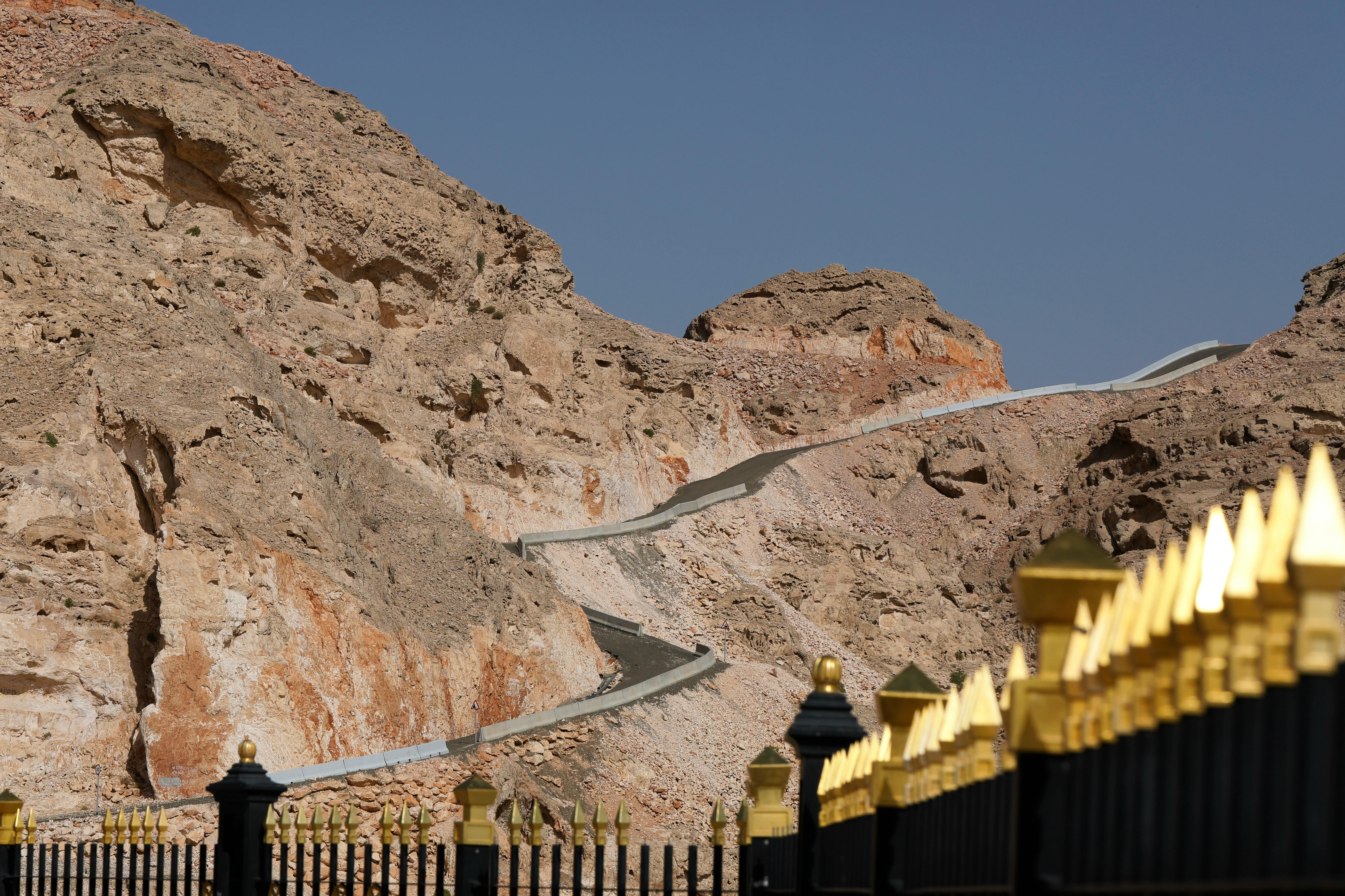 Road and Barren Mountains behind Golden Fence · Free Stock Photo