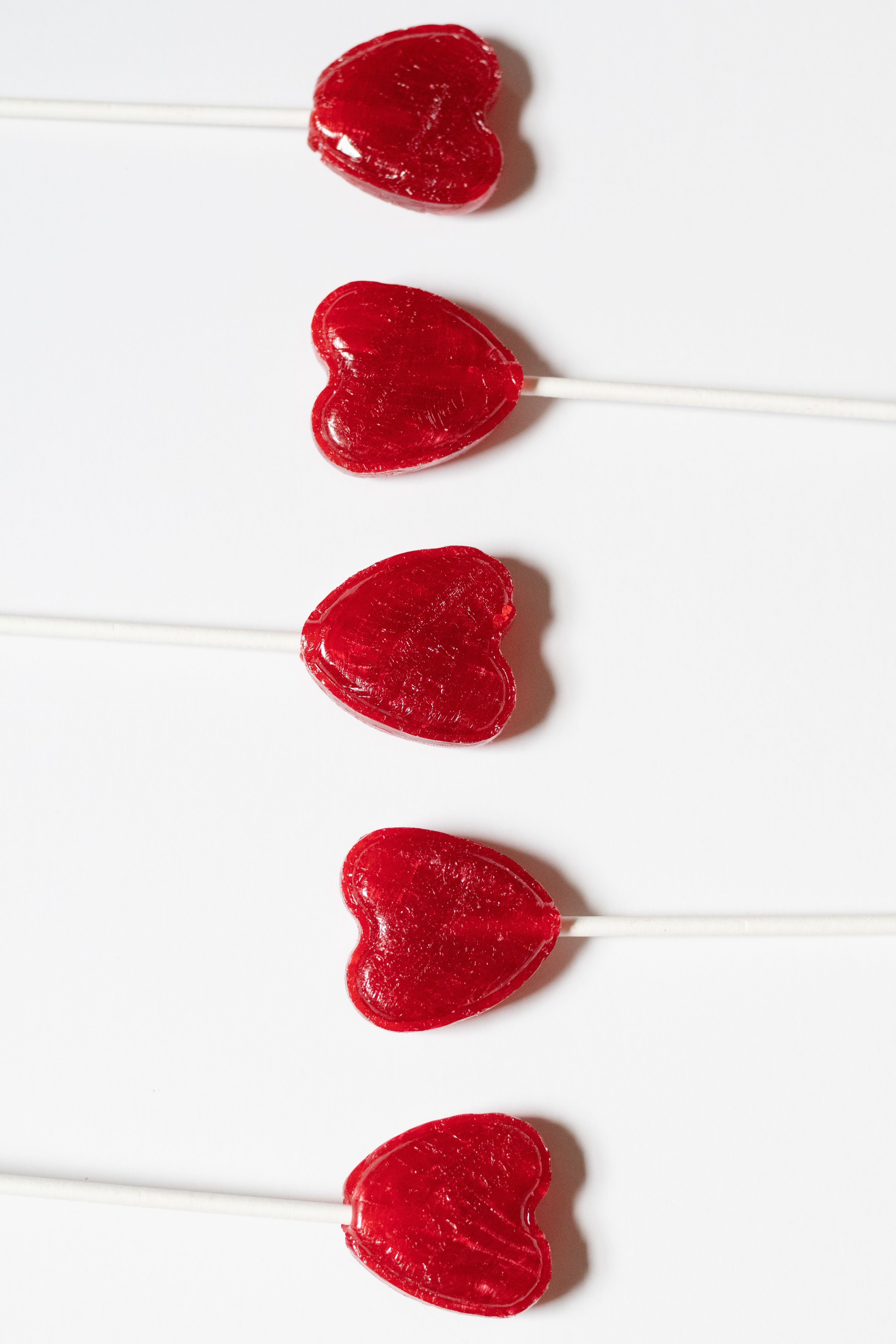 Red heart lollipops on sticks with white background · Free Stock Photo