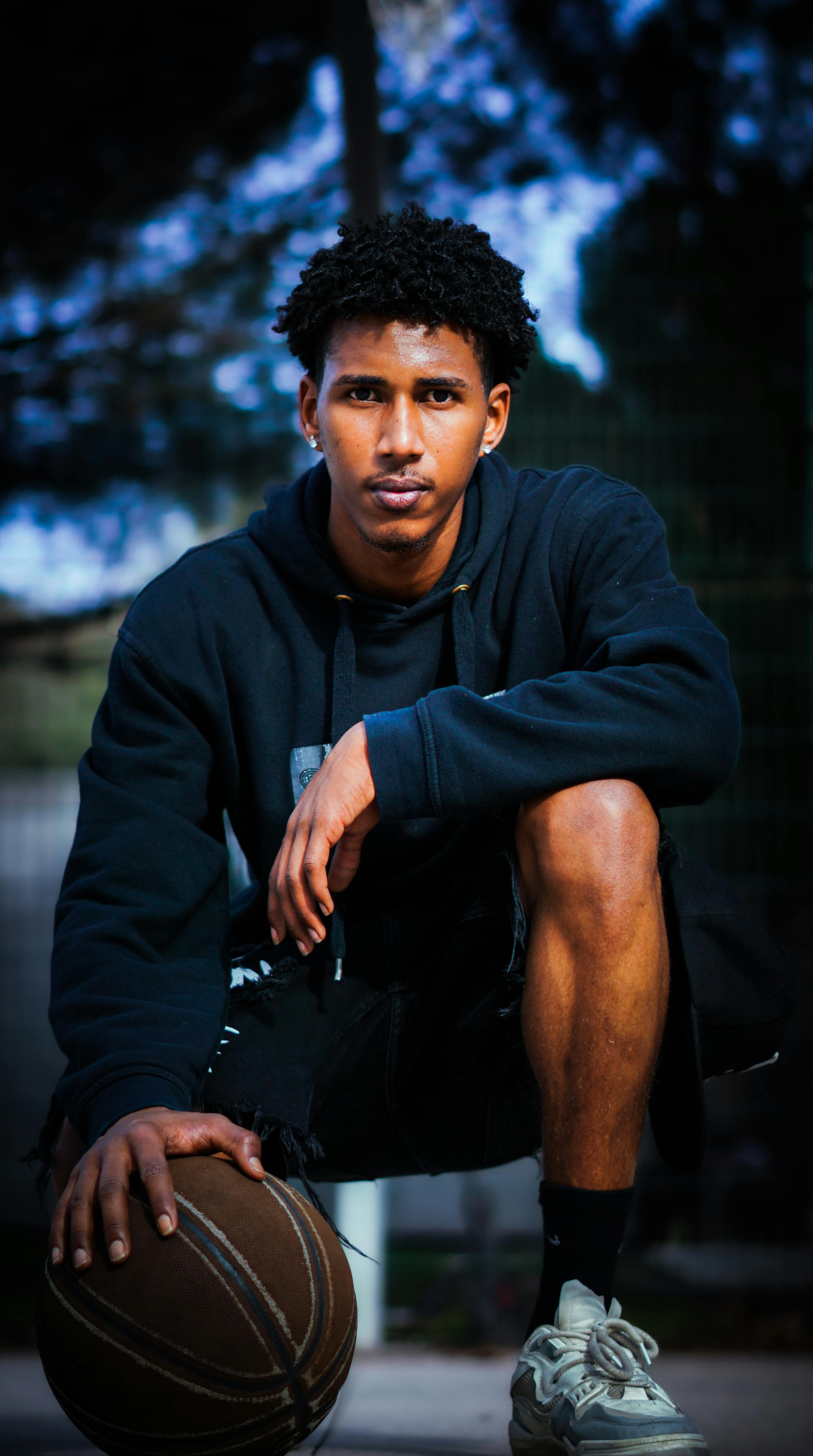 Homem Agachado Com Uma Bola De Basquete · Foto profissional gratuita