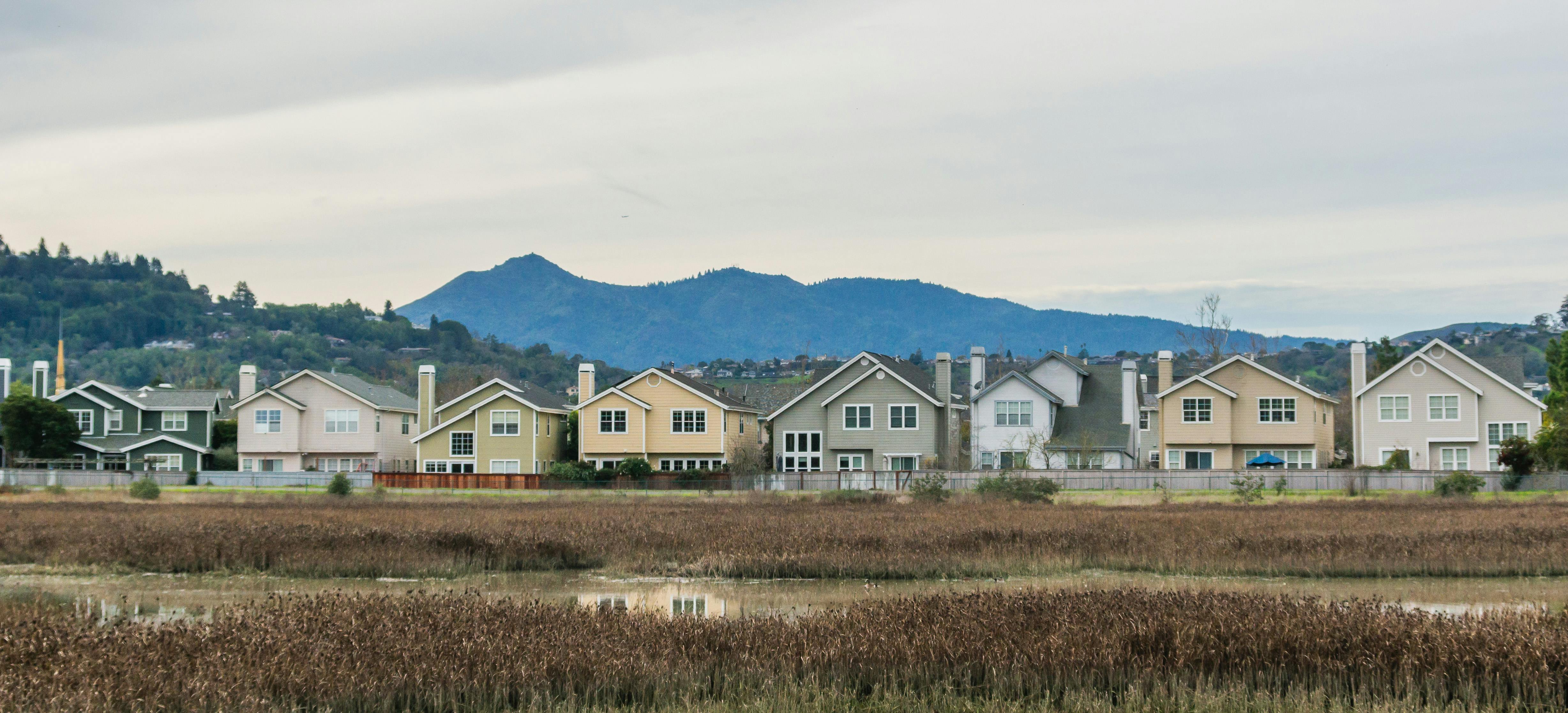 A row of houses in a marshy area with mountains in the background ...