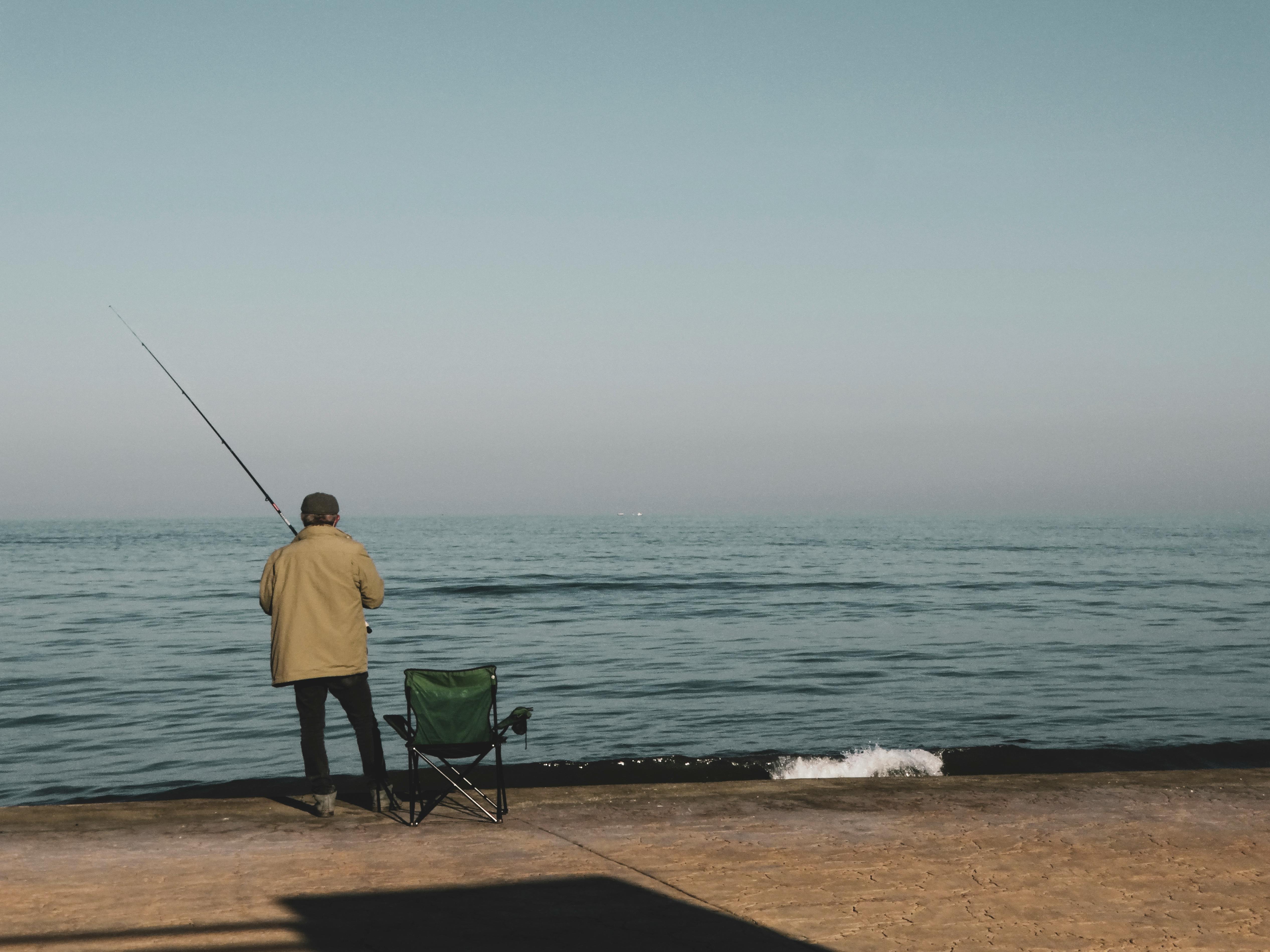 Back View of a Man Fishing from the Shore · Free Stock Photo