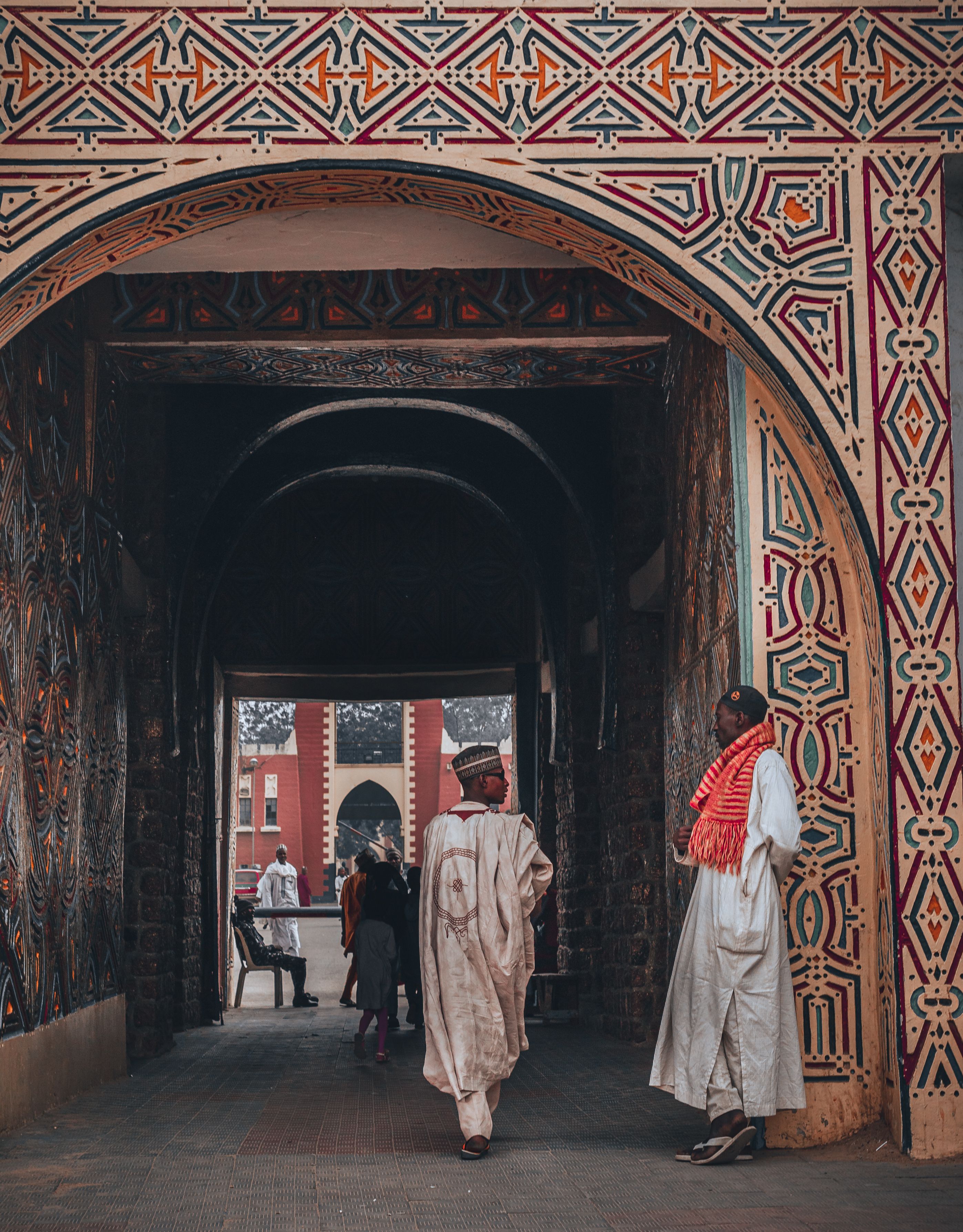 Two men walking through an archway in a city · Free Stock Photo