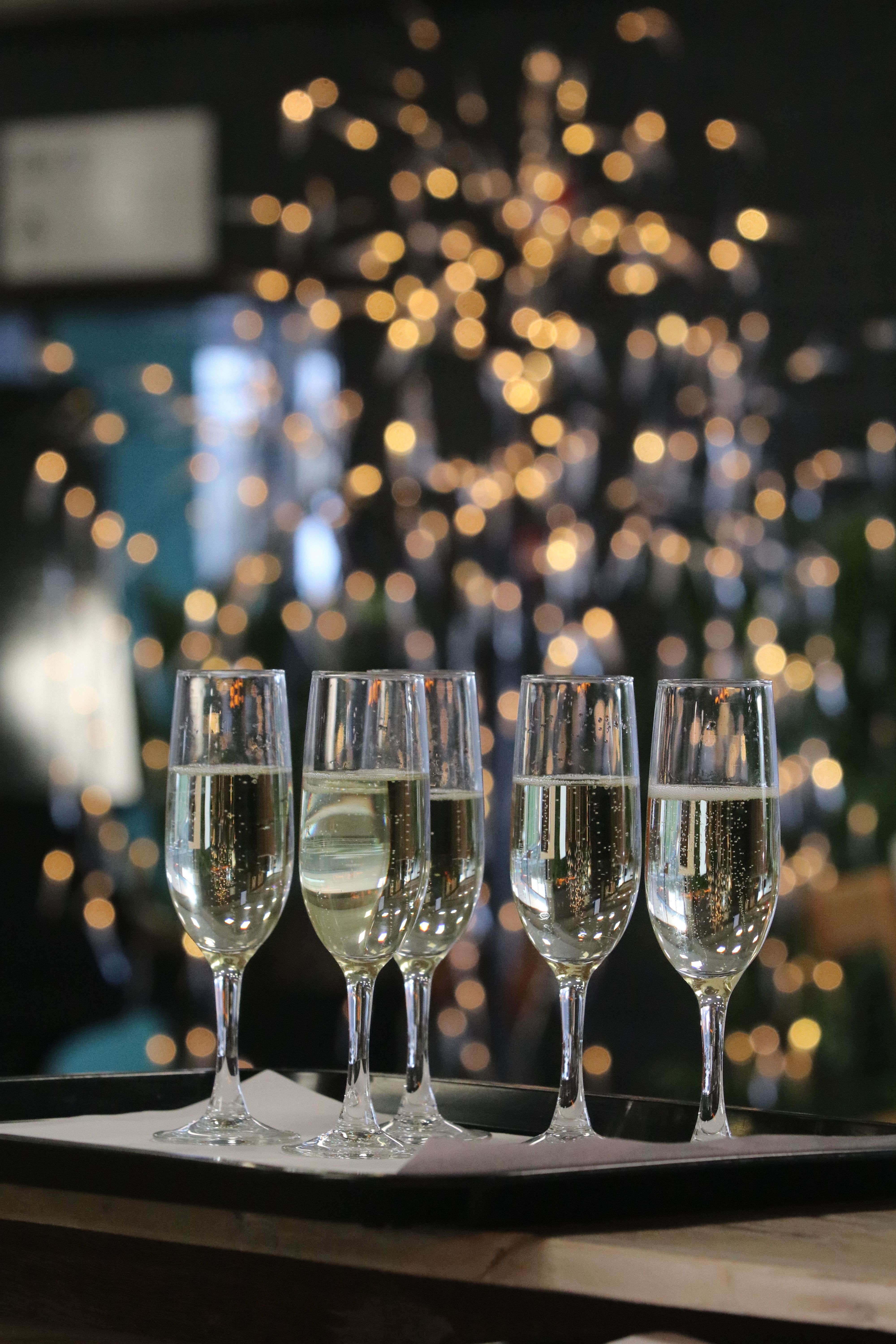 Champagne glasses on a tray with a christmas tree in the background ...