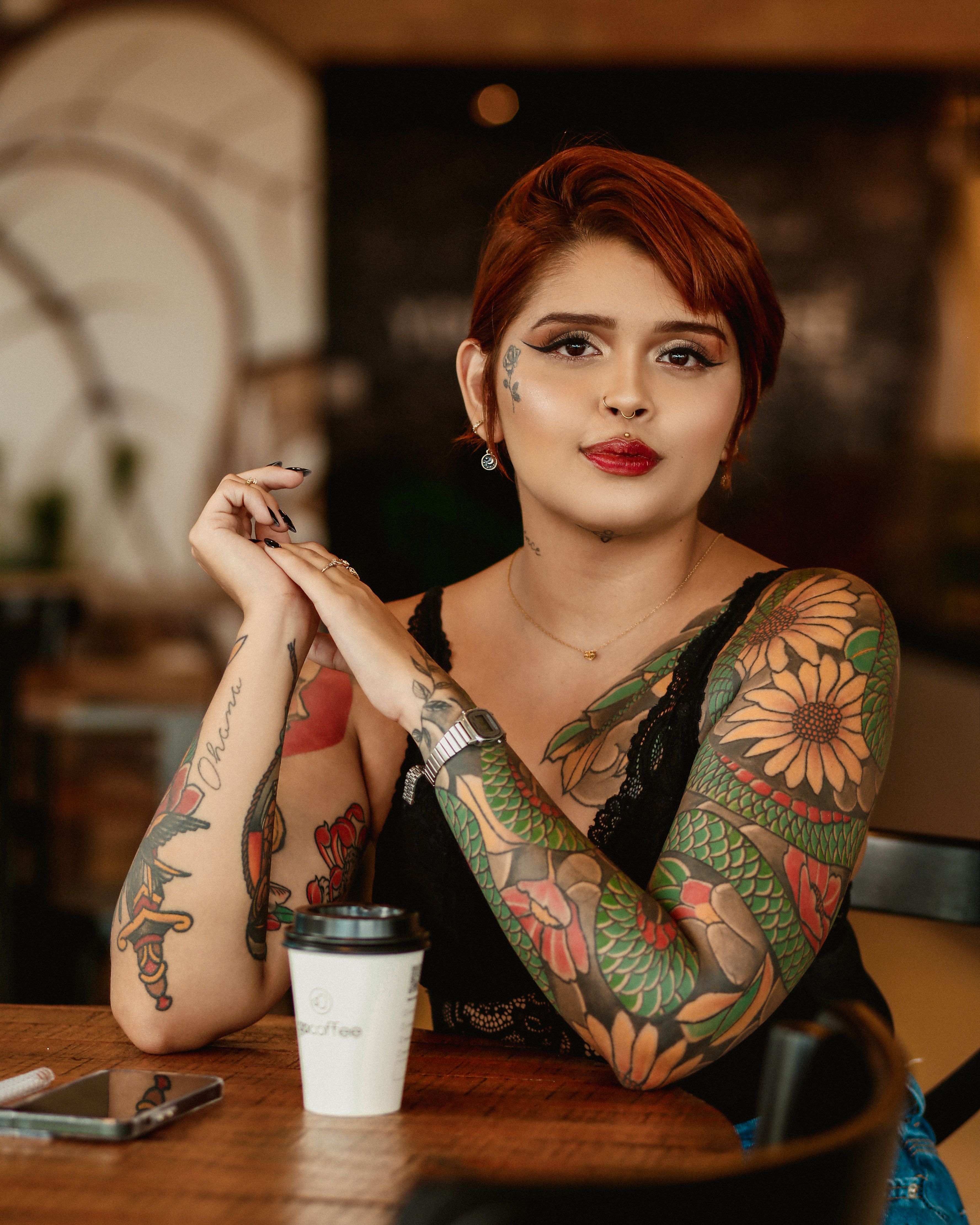 Woman with Tattoos and Short Hair Sitting by Table · Free Stock Photo