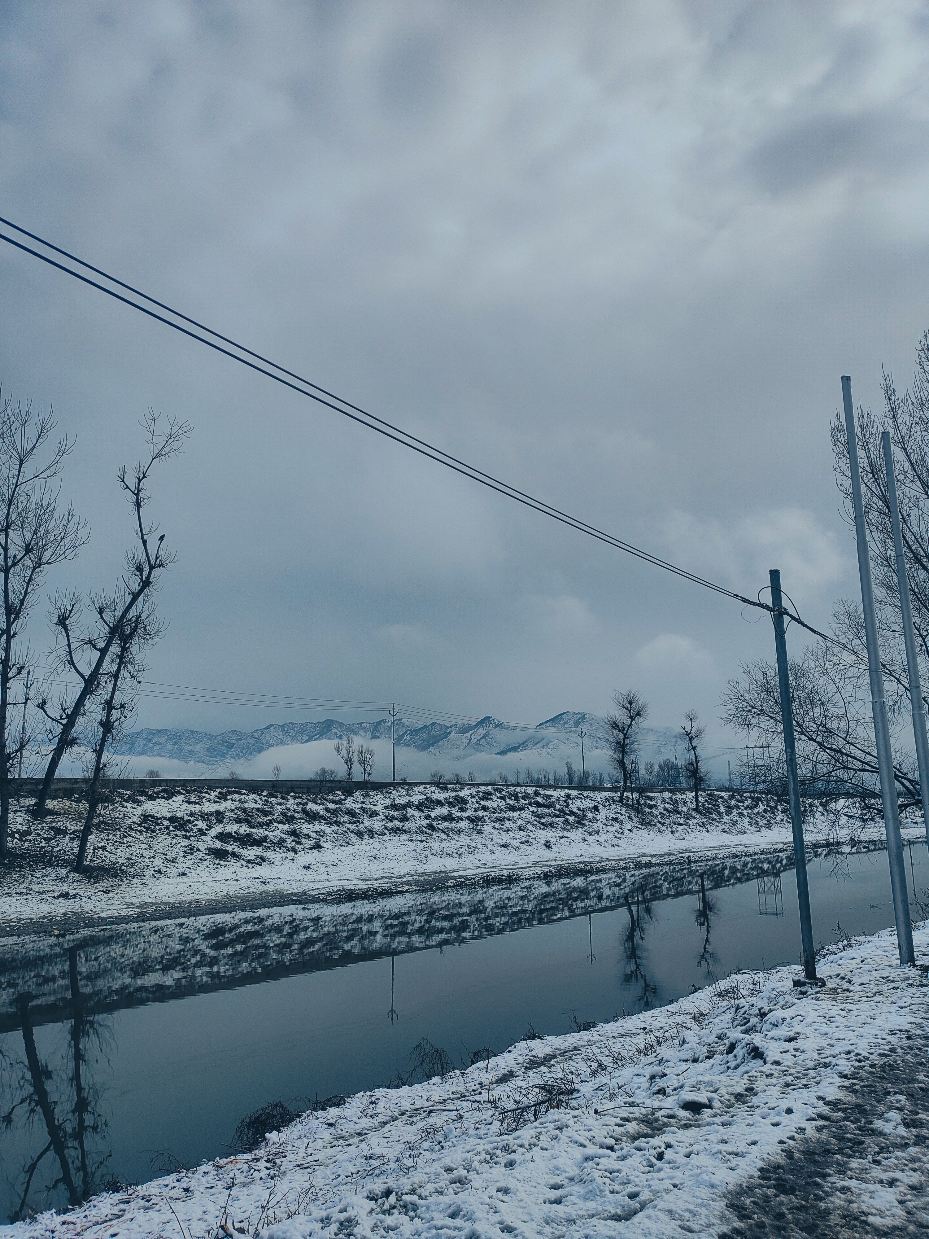 View of a River, Fields Covered in Snow and Mountains in Distance ...