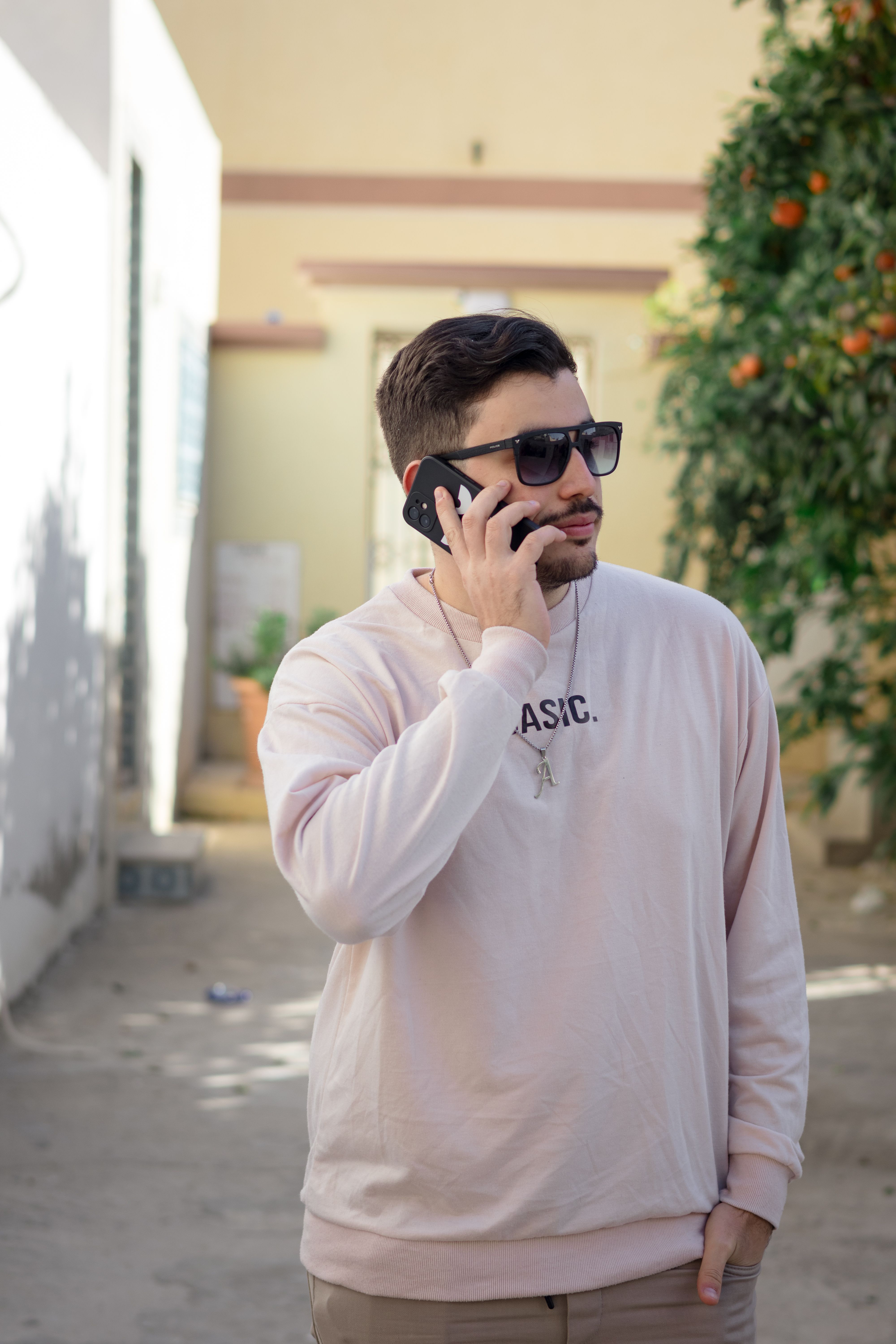 Young Man in a Sweatshirt and Sunglasses Talking on the Phone Outside ...