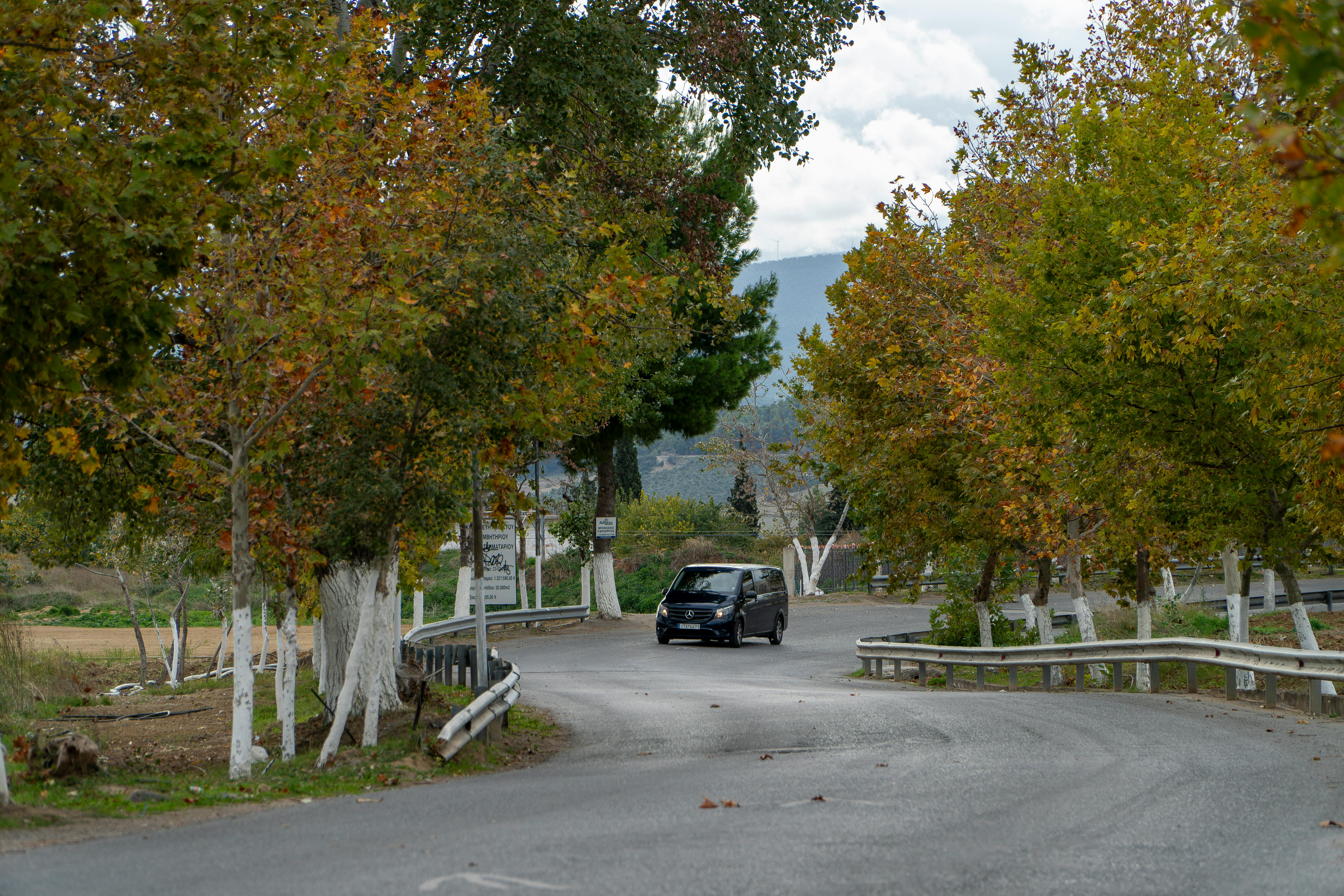 A Car Driving on a Road between Autumnal Trees in the Countryside ...