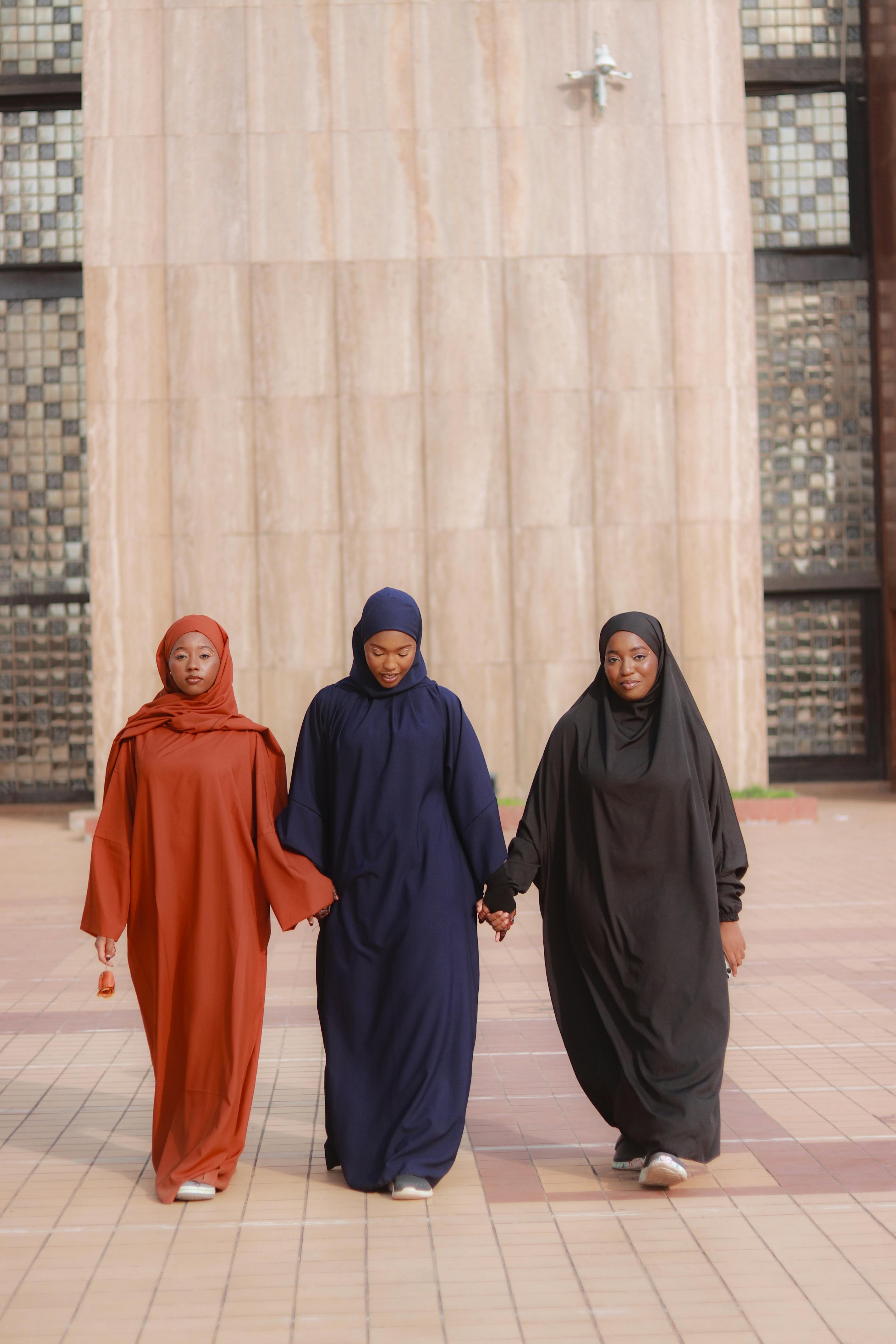 Three Women in Traditional Attire Walking Outdoors · Free Stock Photo