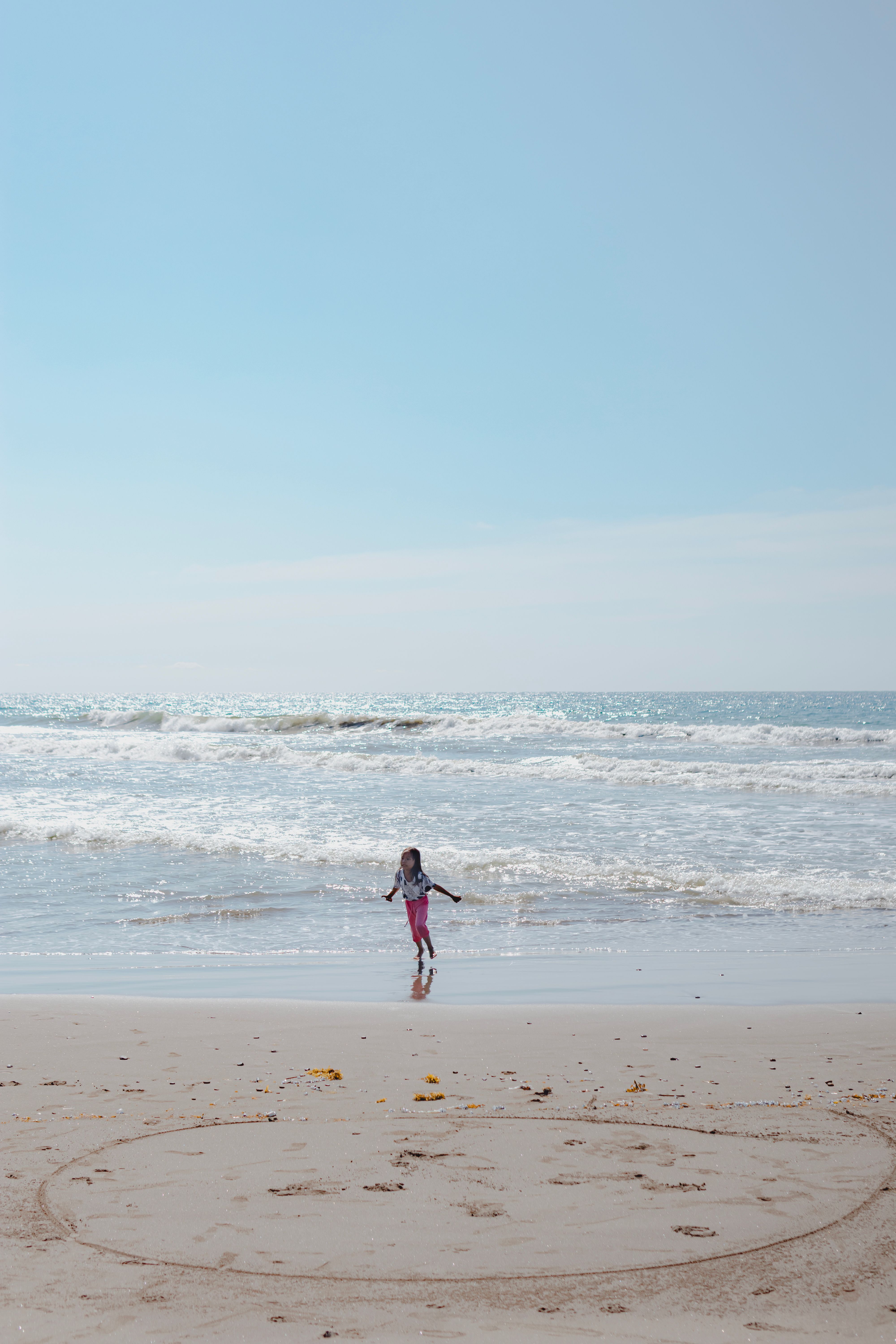 Little Girl Running Away from a Wave on the Beach · Free Stock Photo
