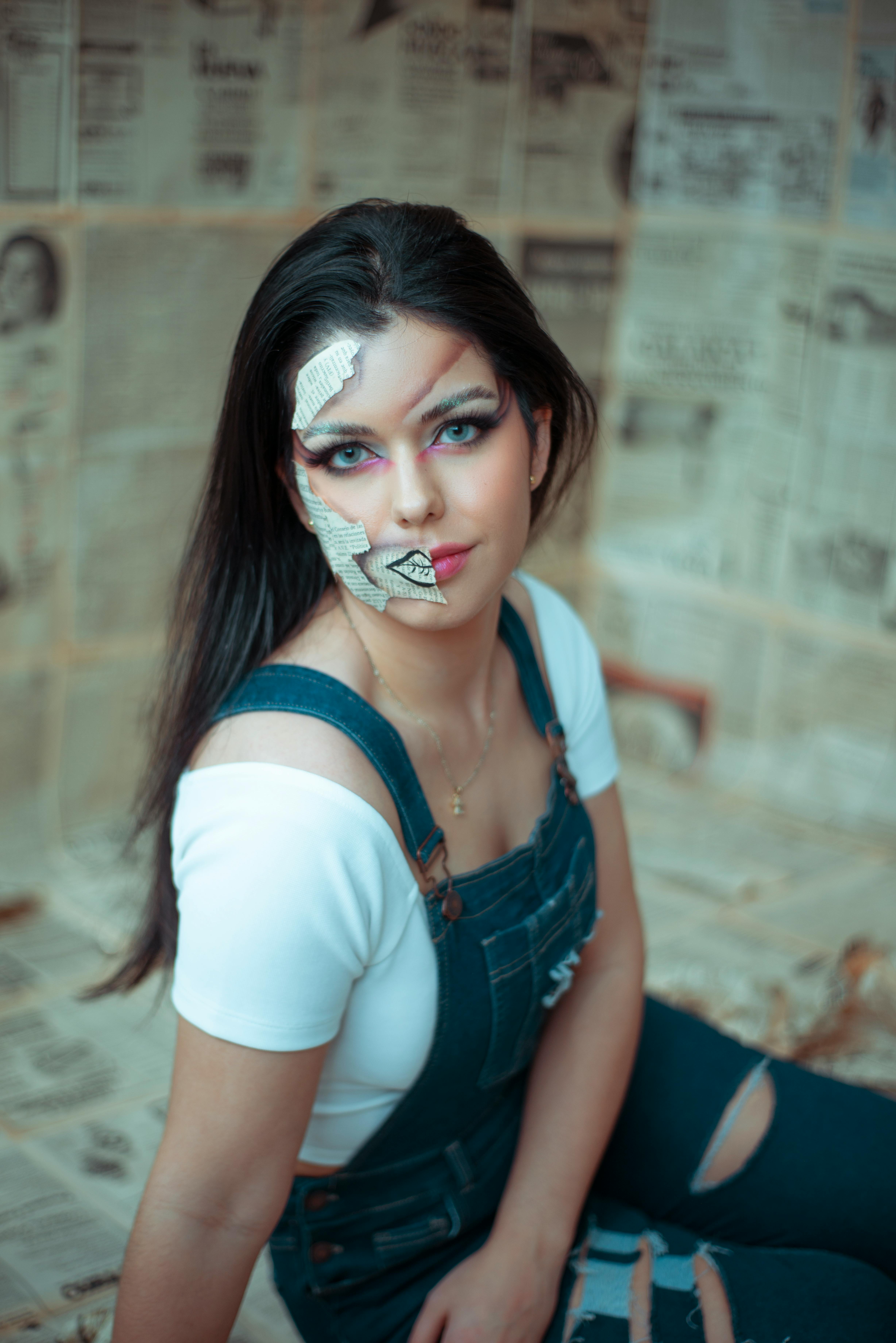 Model with Artistic Makeup Wearing Distressed Denim Overalls in a Room ...